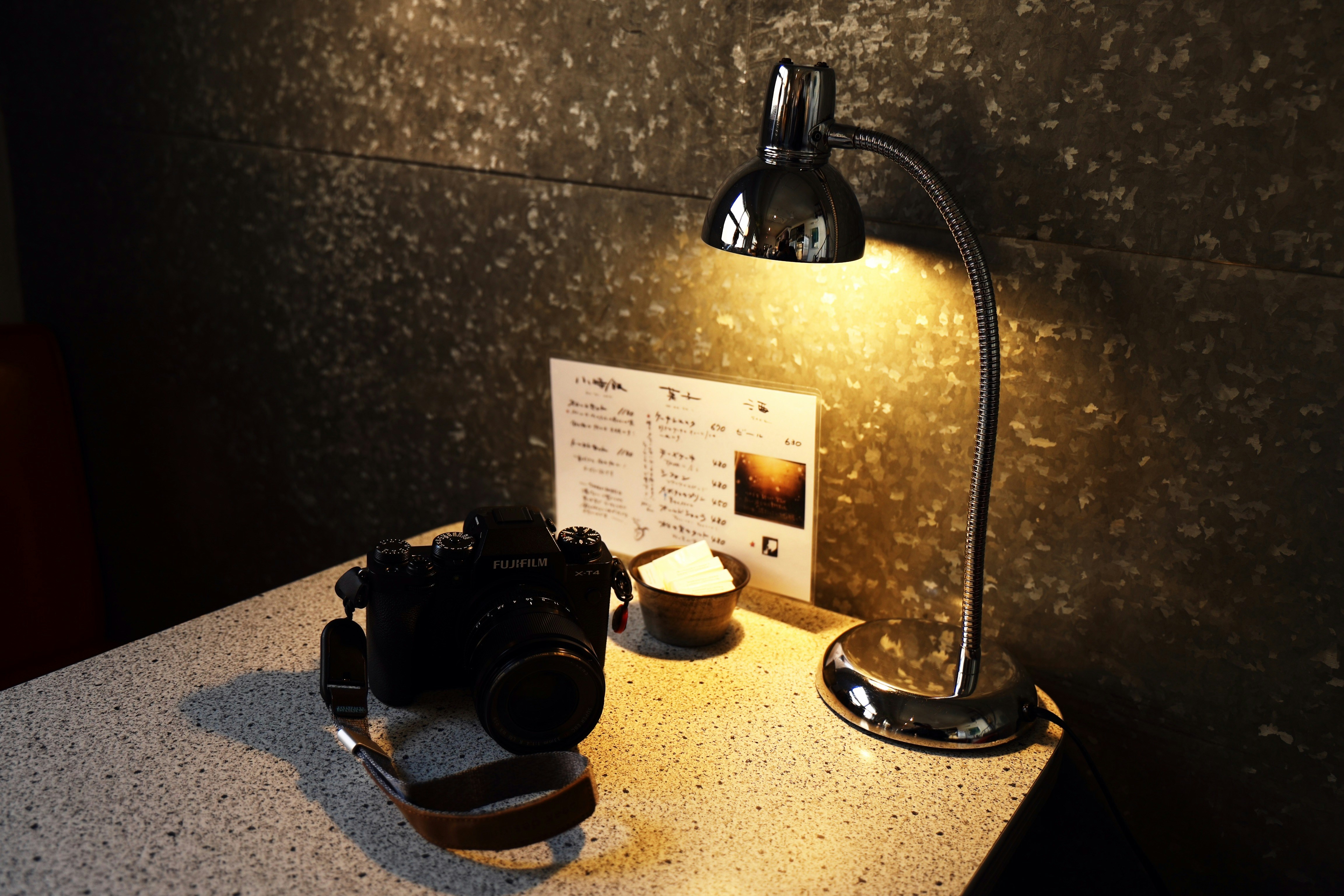 Lamp-lit Still Life: A Canon on a Quiet Counter Under a Curved Desk Lamp