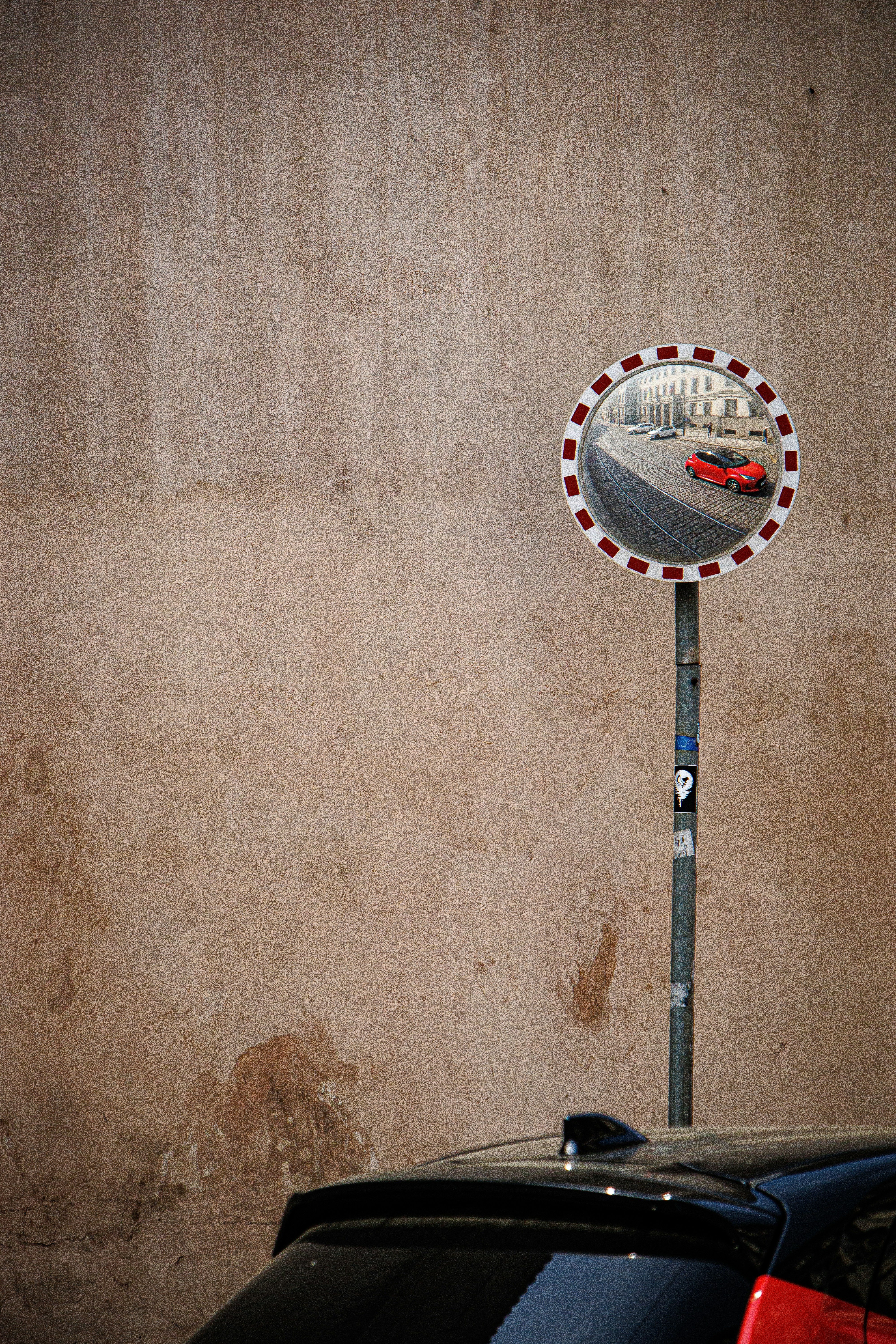 Mirror of a Street: Circular Sign Reflecting a Red Car