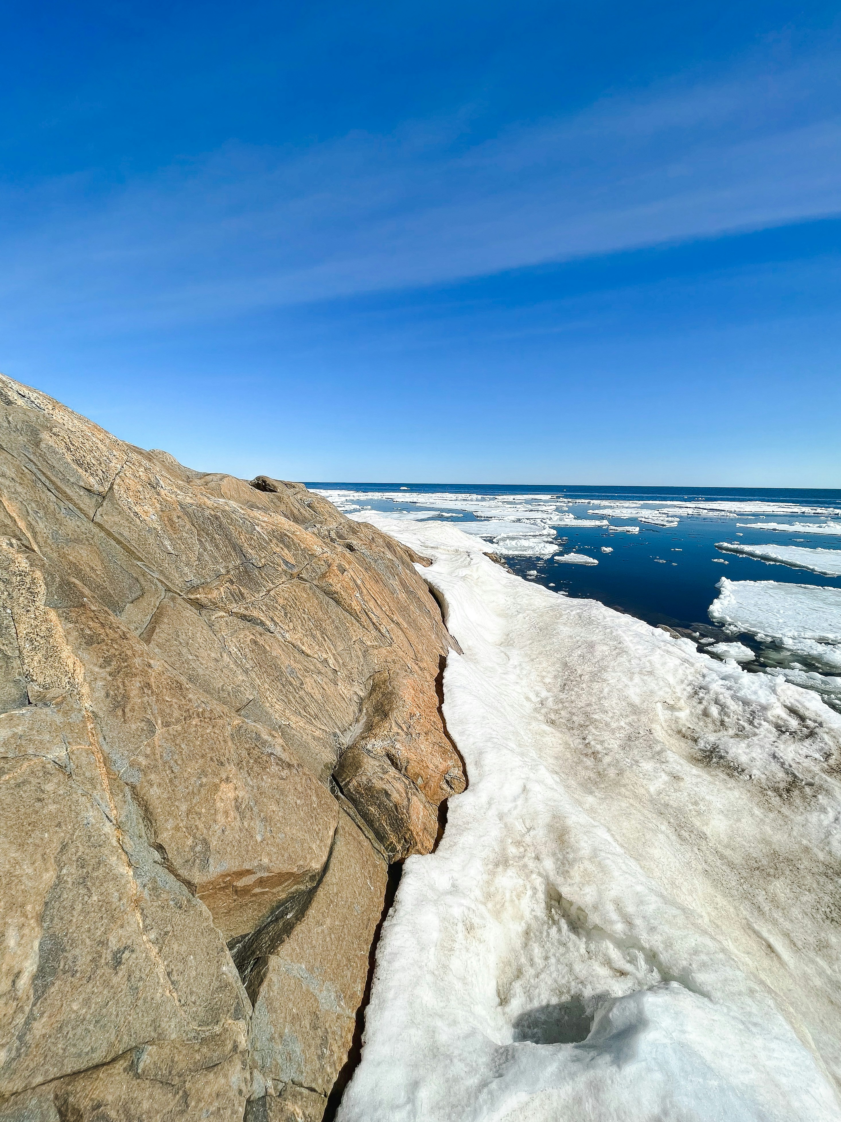 Rugged shoreline dialogue: rock ledge meeting a frozen, sunlit sea