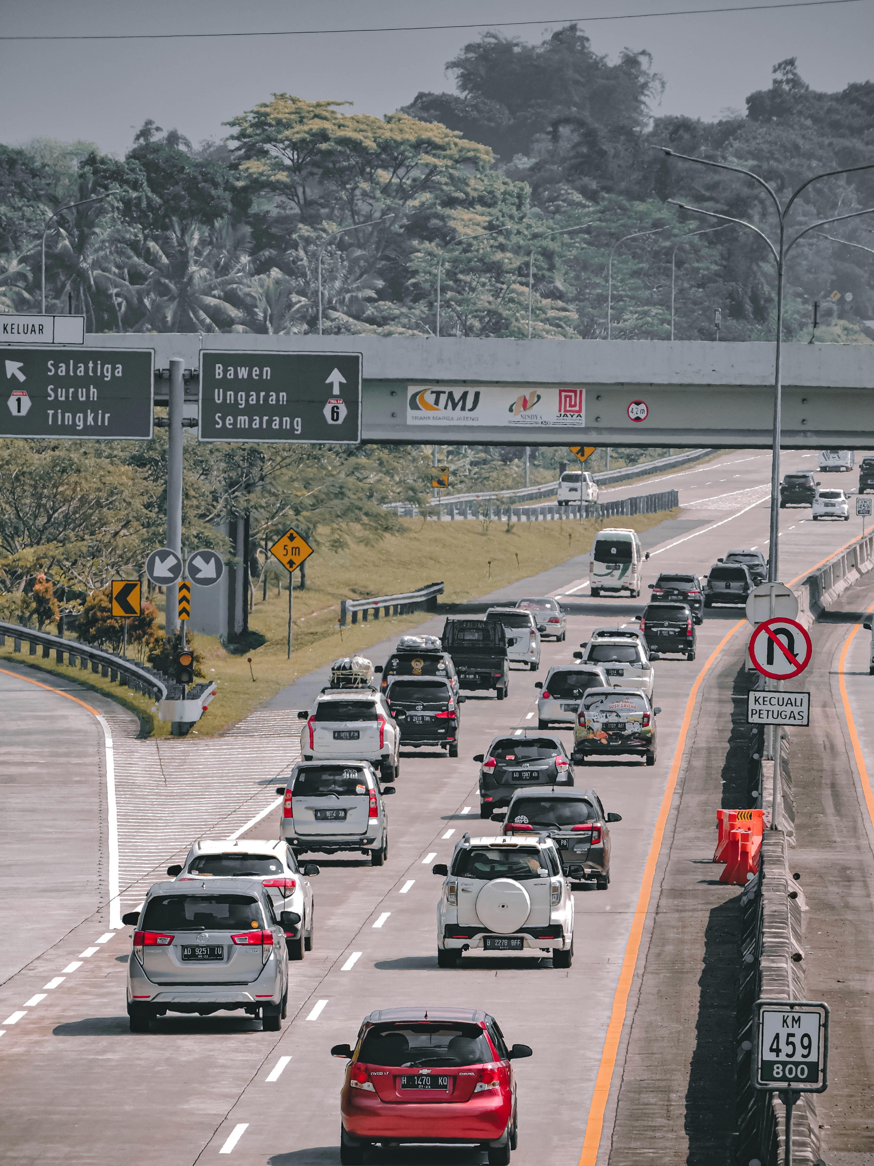 A busy highway scene captured from an elevated perspective, showcasing a variety of vehicles in motion under clear skies and road signage.