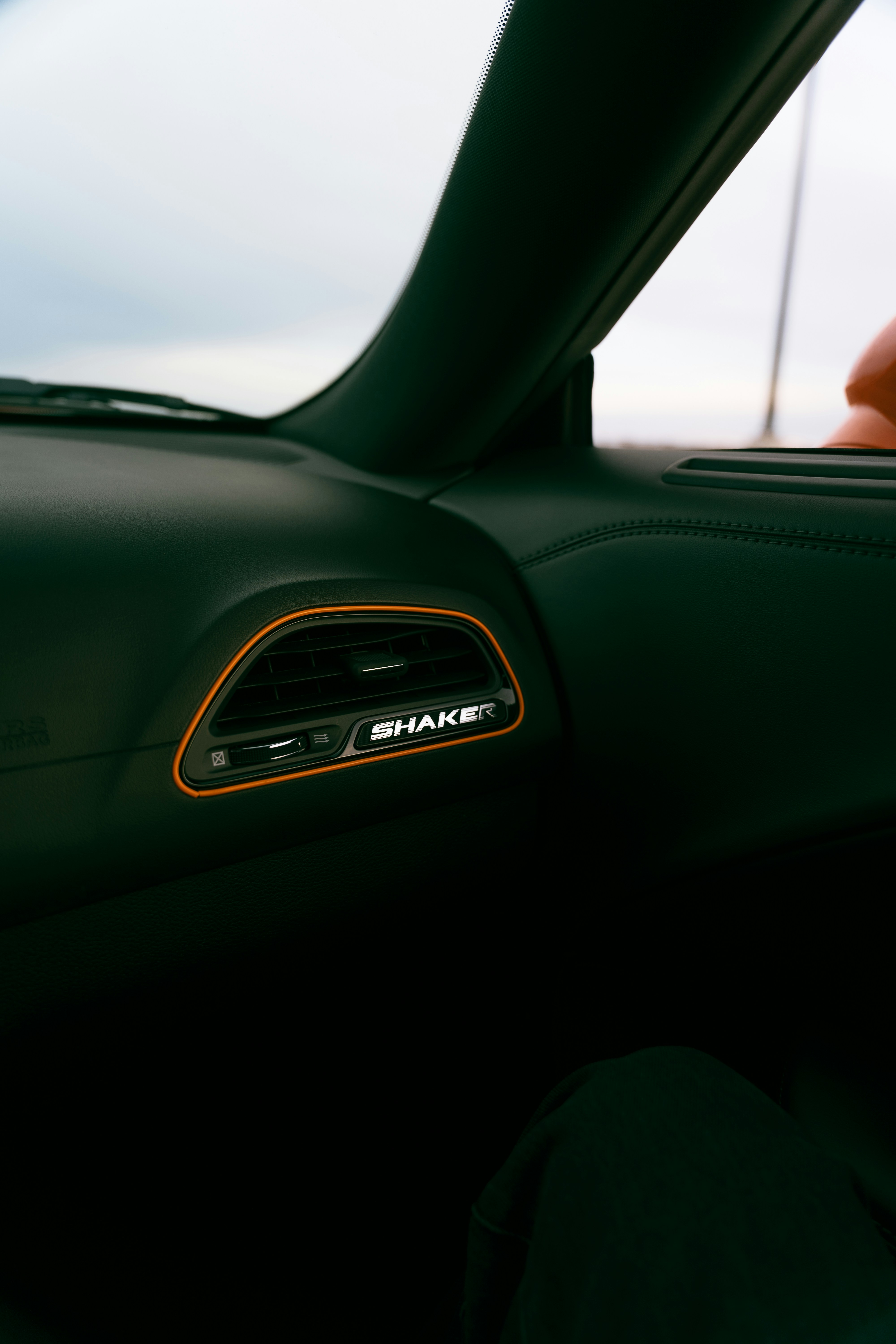 Close-up of a car's interior featuring the Shaker audio system emblem, highlighting the sleek design and craftsmanship of modern automotive interiors.