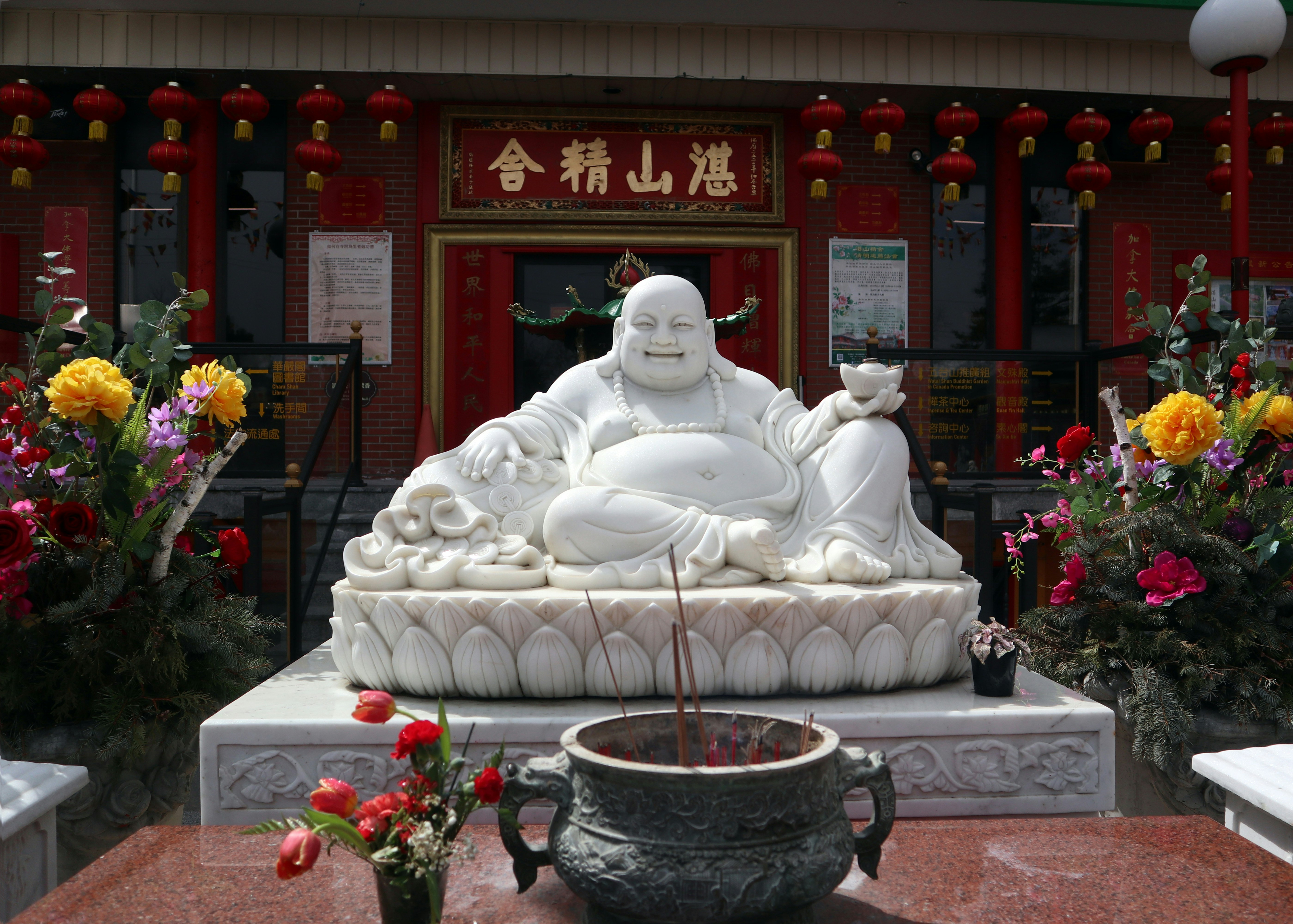 Flowers and incense candles surround a resting Buddha statue in Thornhill's Cham Shan Temple.