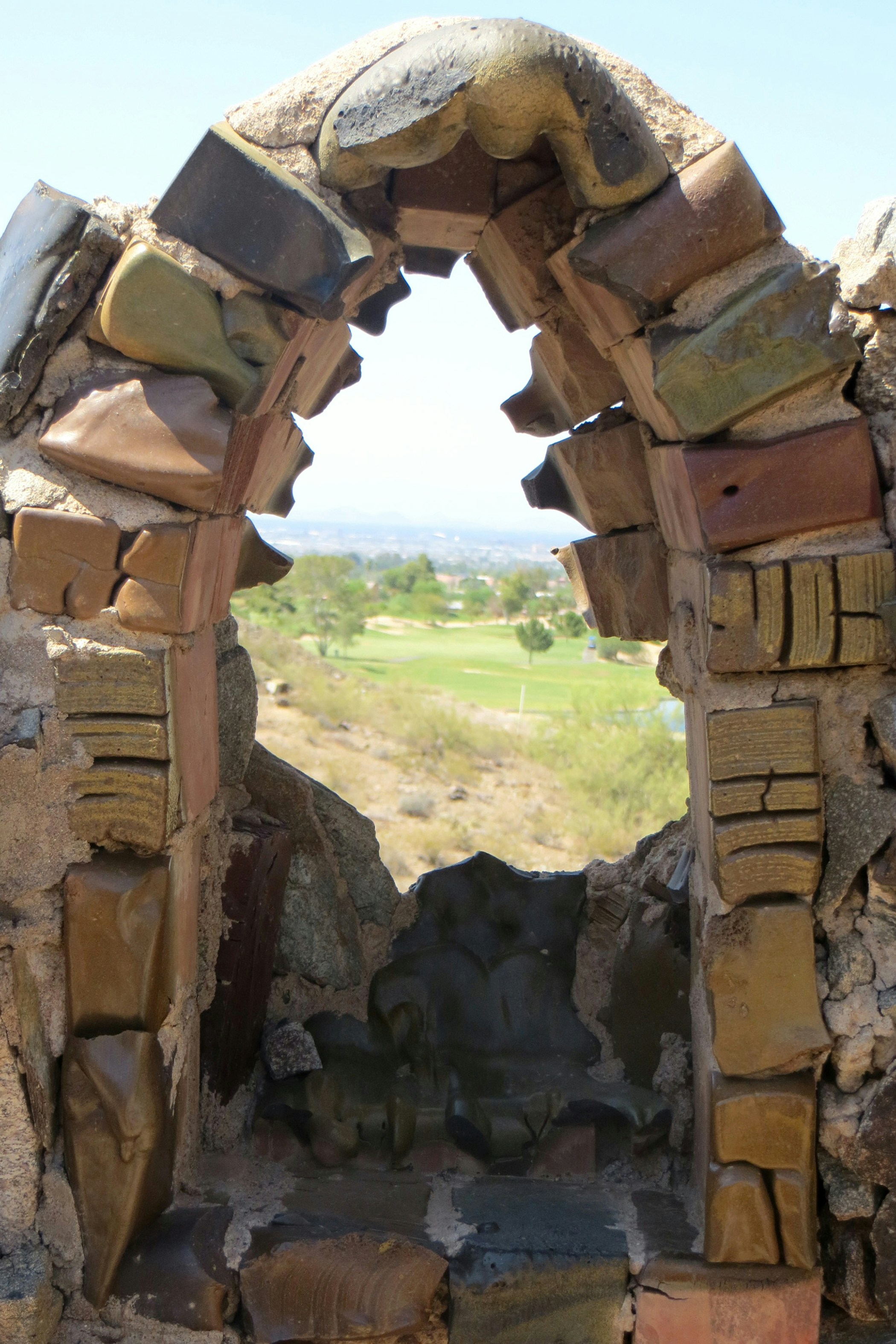 A weathered stone archway reveals a lush green landscape beyond, showcasing the contrast between man-made structures and the natural world.