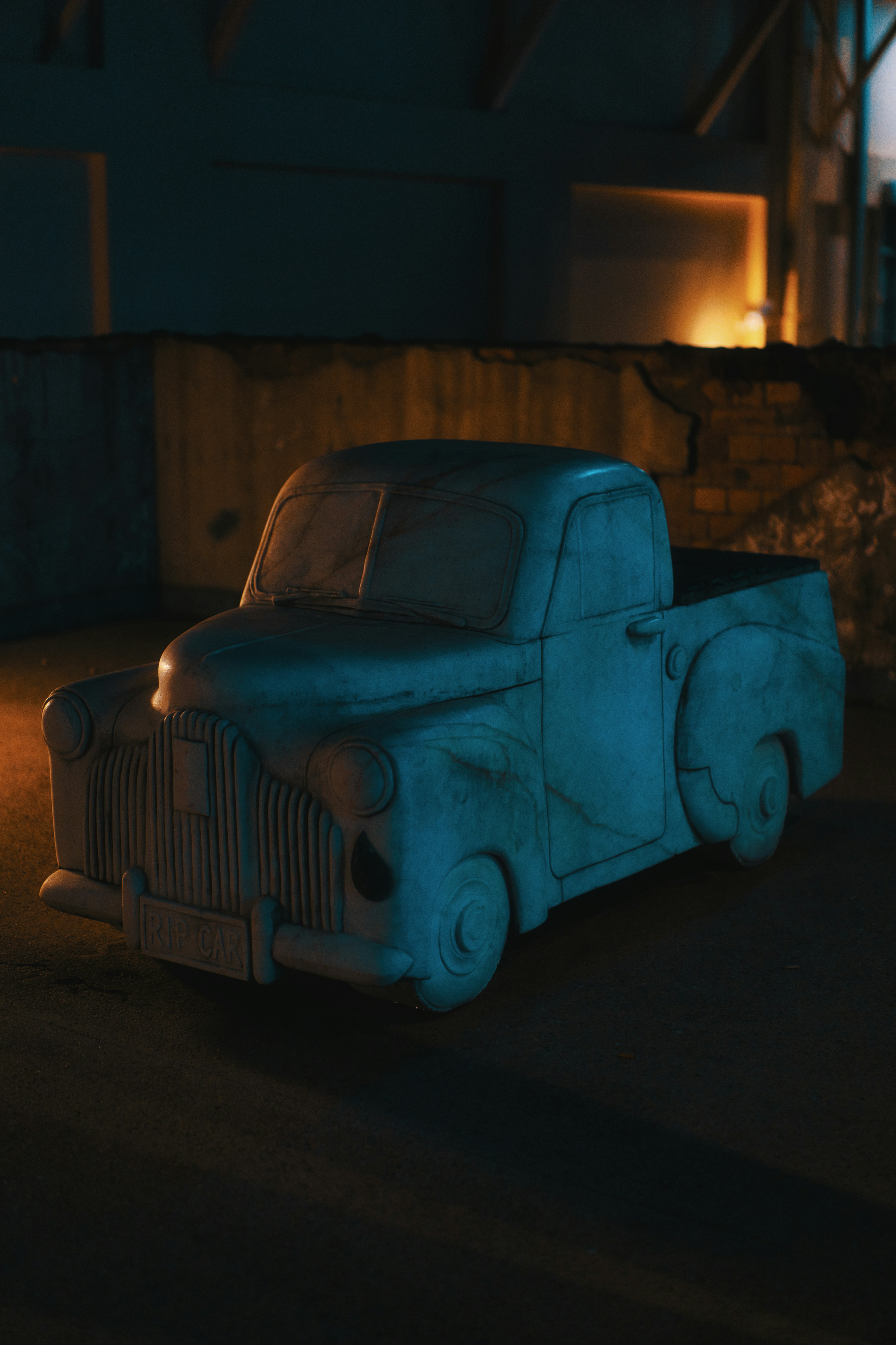 A vintage truck sculpture illuminated by soft, ambient light, casting an ethereal glow in a dimly lit environment.