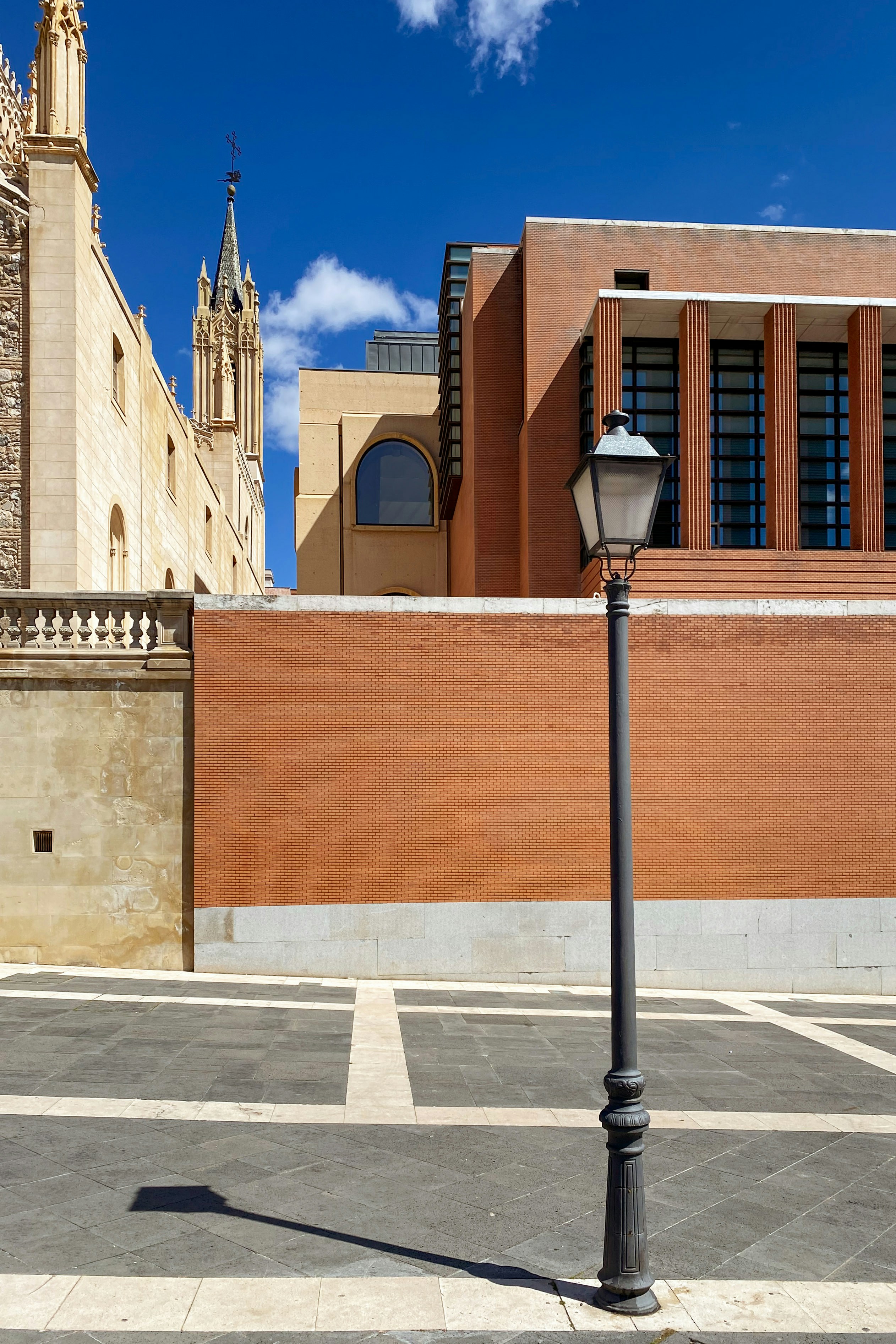 Solitary Lamppost Framed by Brick Architecture Under a Clear Blue Sky