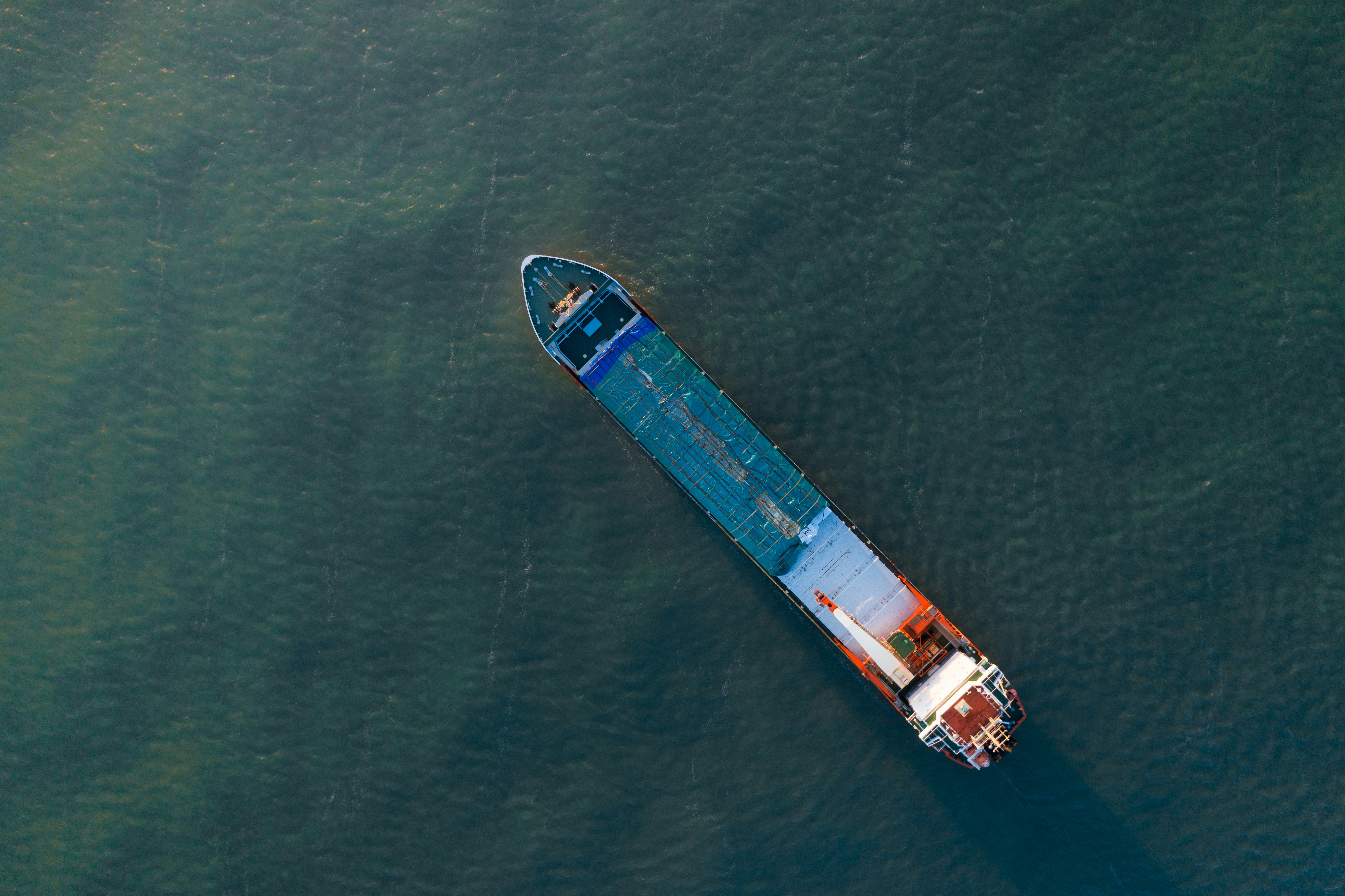 Cargo ship gliding smoothly over calm waters, showcasing its vibrant colors and intricate deck details.