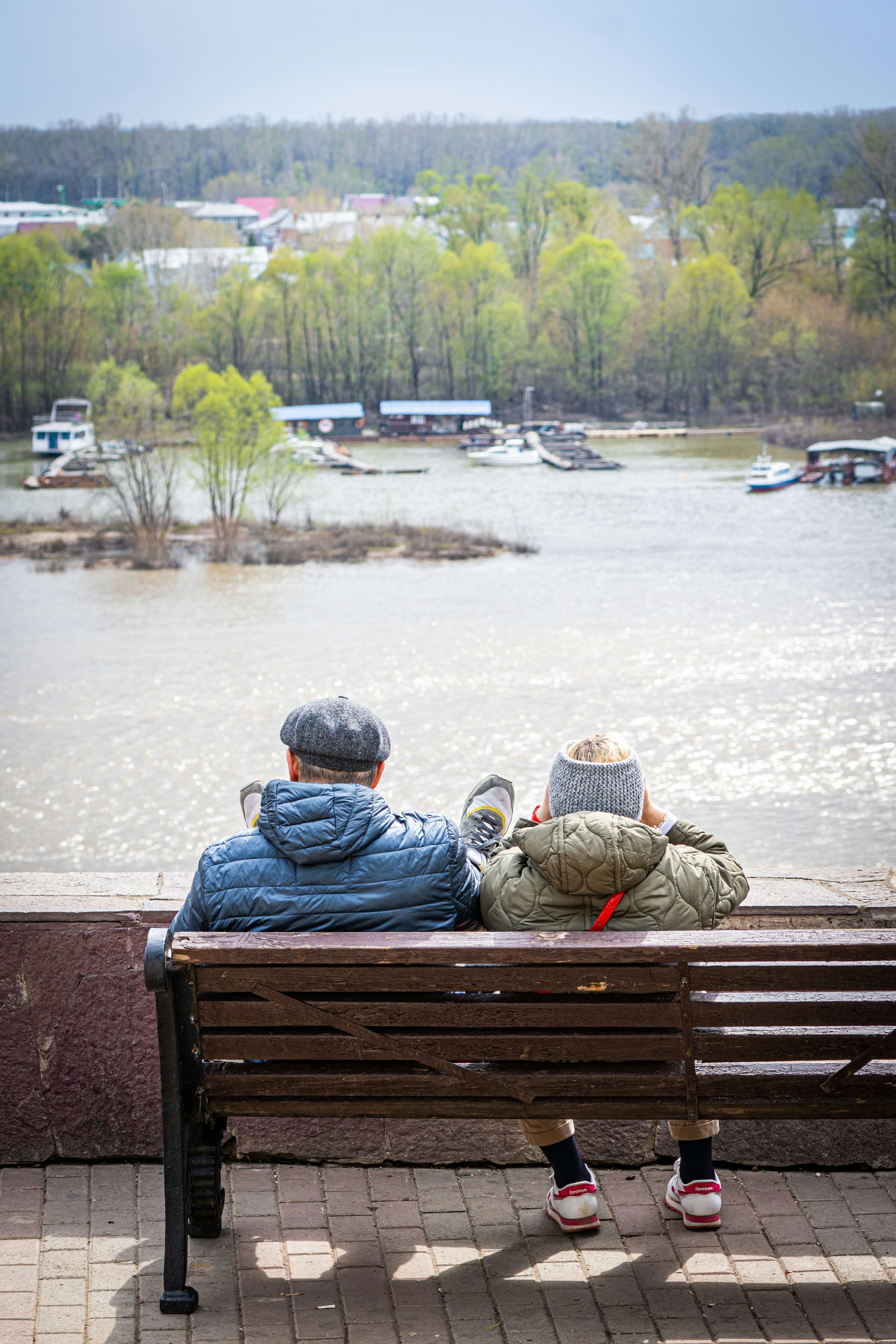A couple of people sit on a bench by a river photo – Free Ufa Image on Unsplash