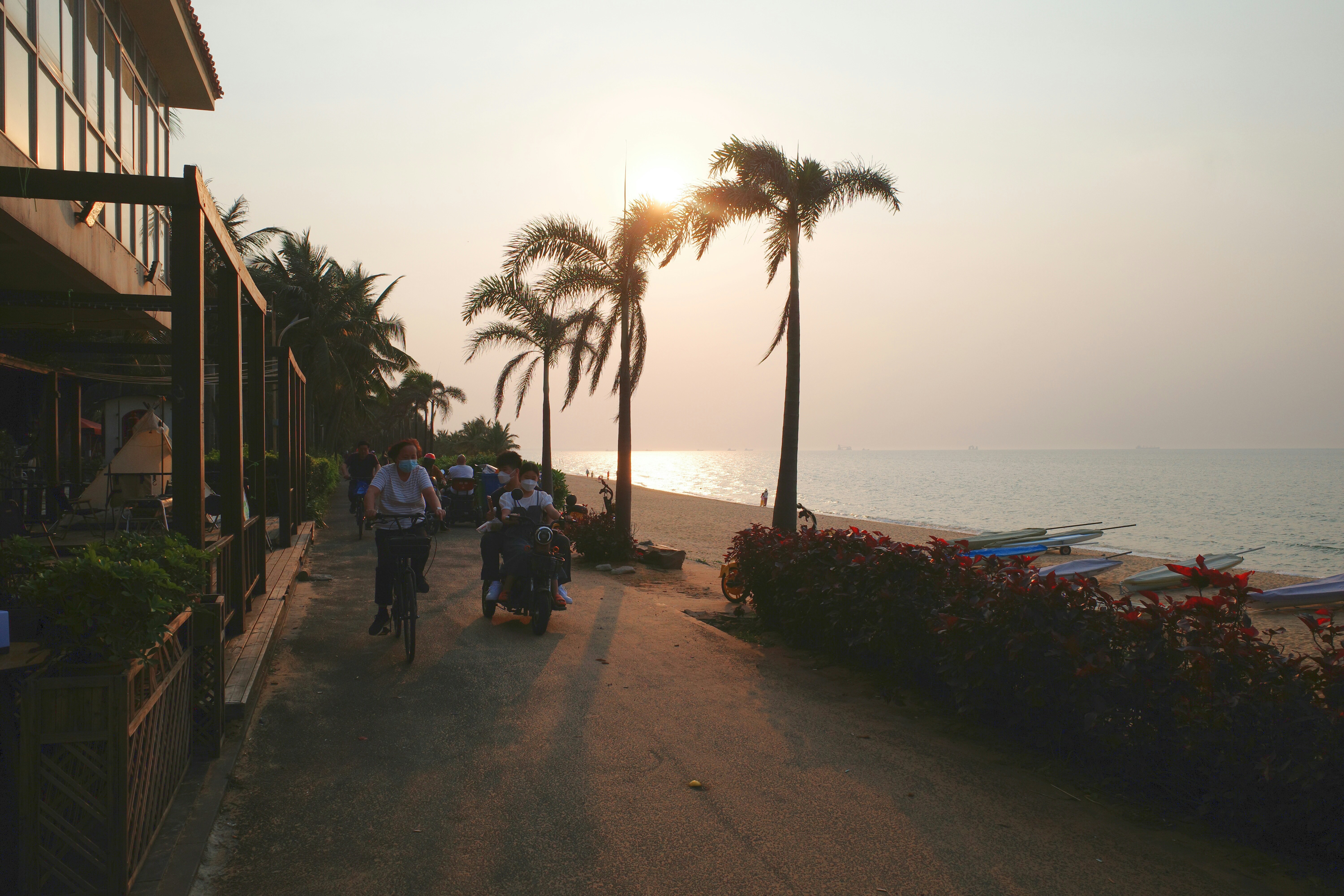 a person riding a bicycle down a sidewalk next to a beach
