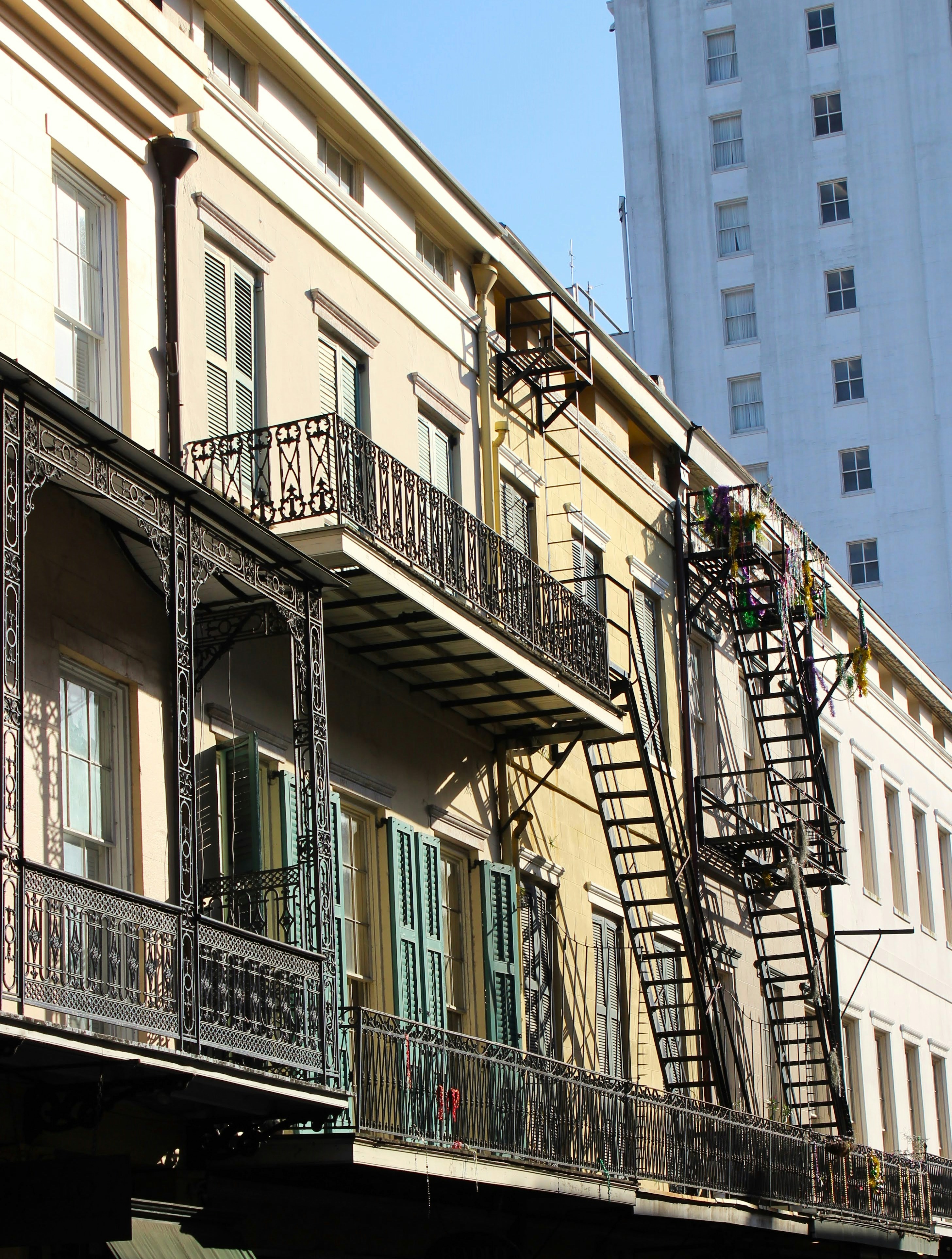 Sunlit Iron Lace: Balconies and a Fire Escape Along a Historic Facade
