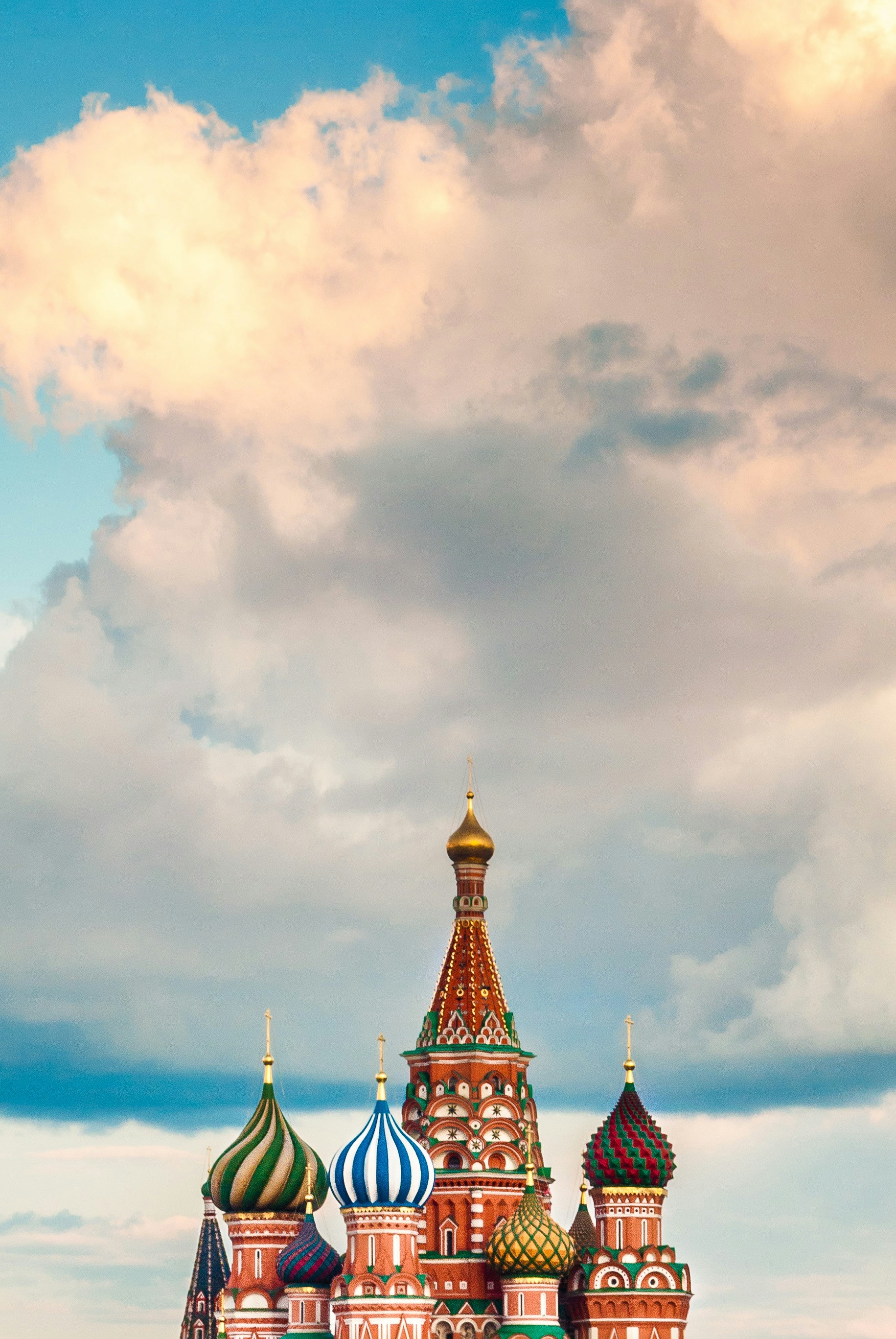 Colorful onion domes of St. Basil's Cathedral rise majestically under a cloudy sky, showcasing intricate patterns and vibrant hues.