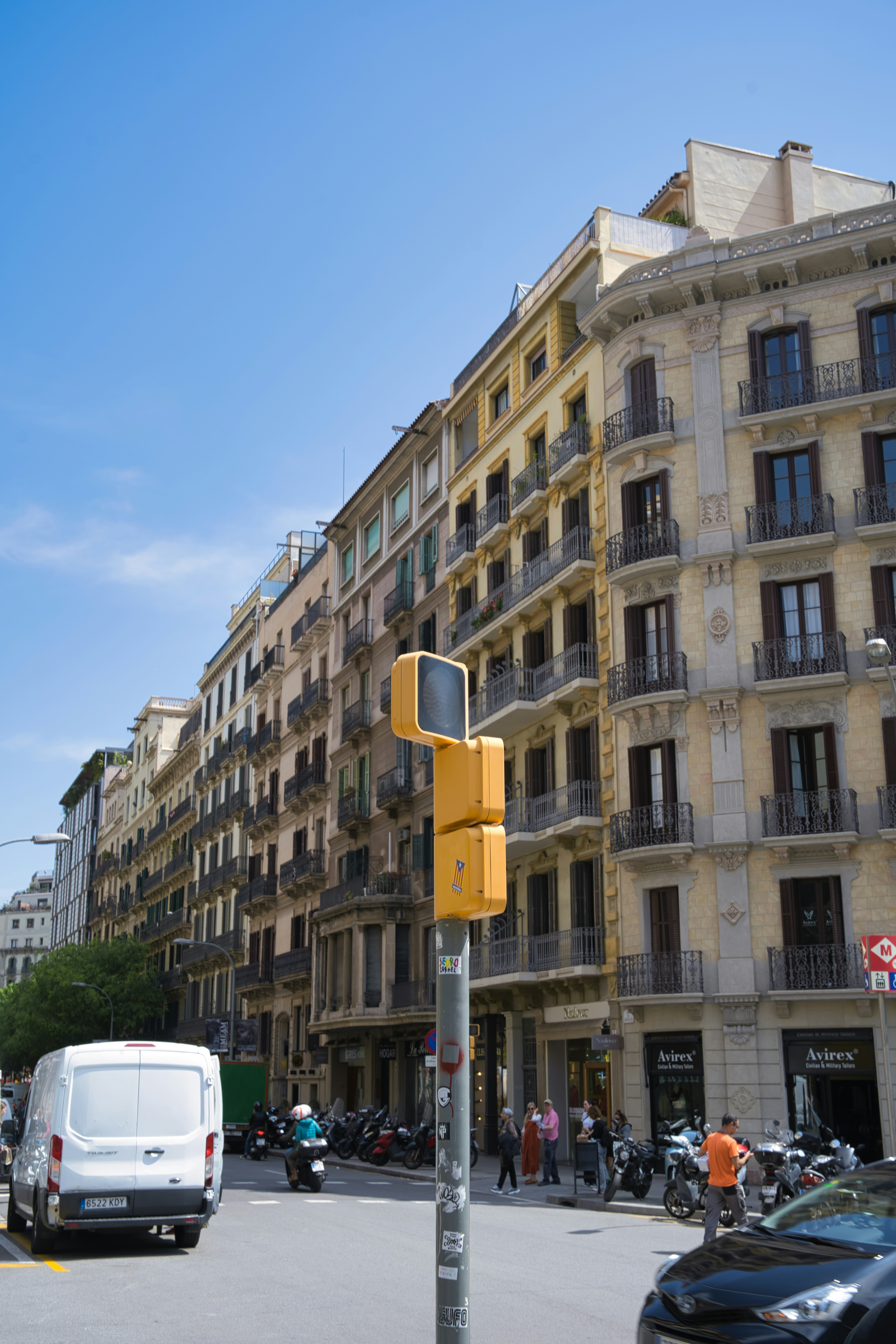 Historic buildings line a bustling street, showcasing a blend of architectural styles. A traffic signal stands prominently, guiding the flow of pedestrians and vehicles.