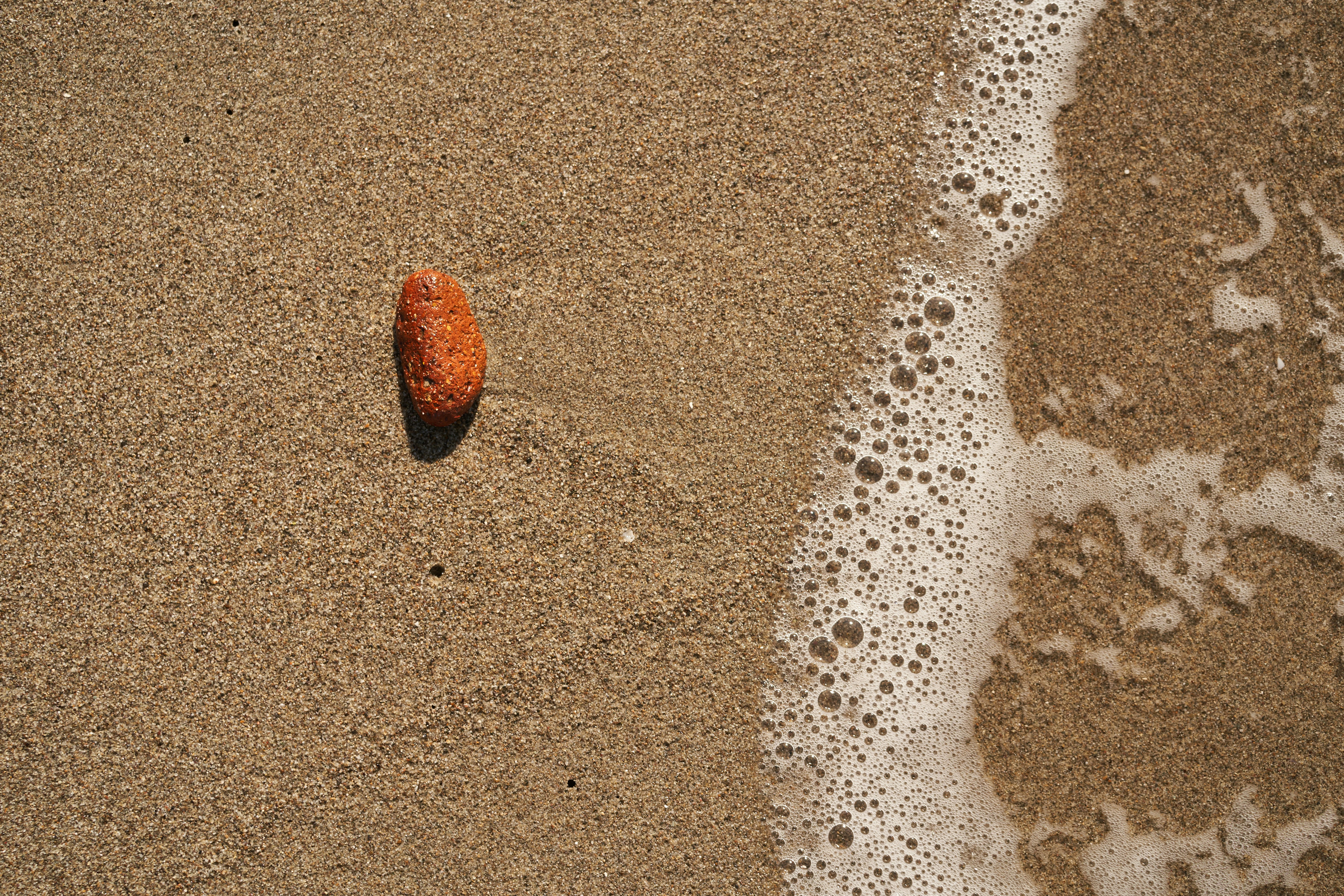 Un petit objet rouge et noir sur une surface sablonneuse photo – Photo ...