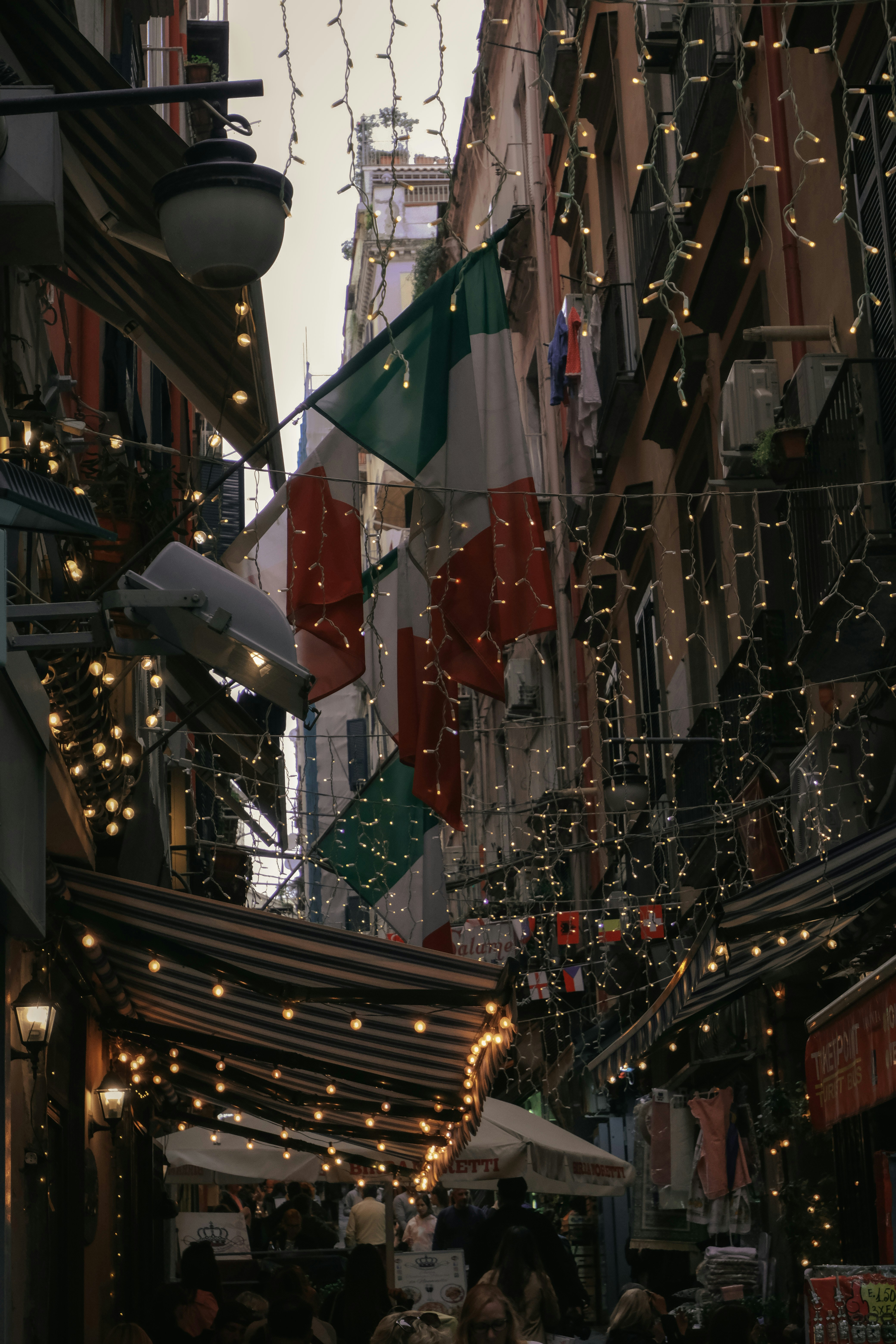 Lantern-Laced Alley: Italian Flags Draped Over a Dusk Market