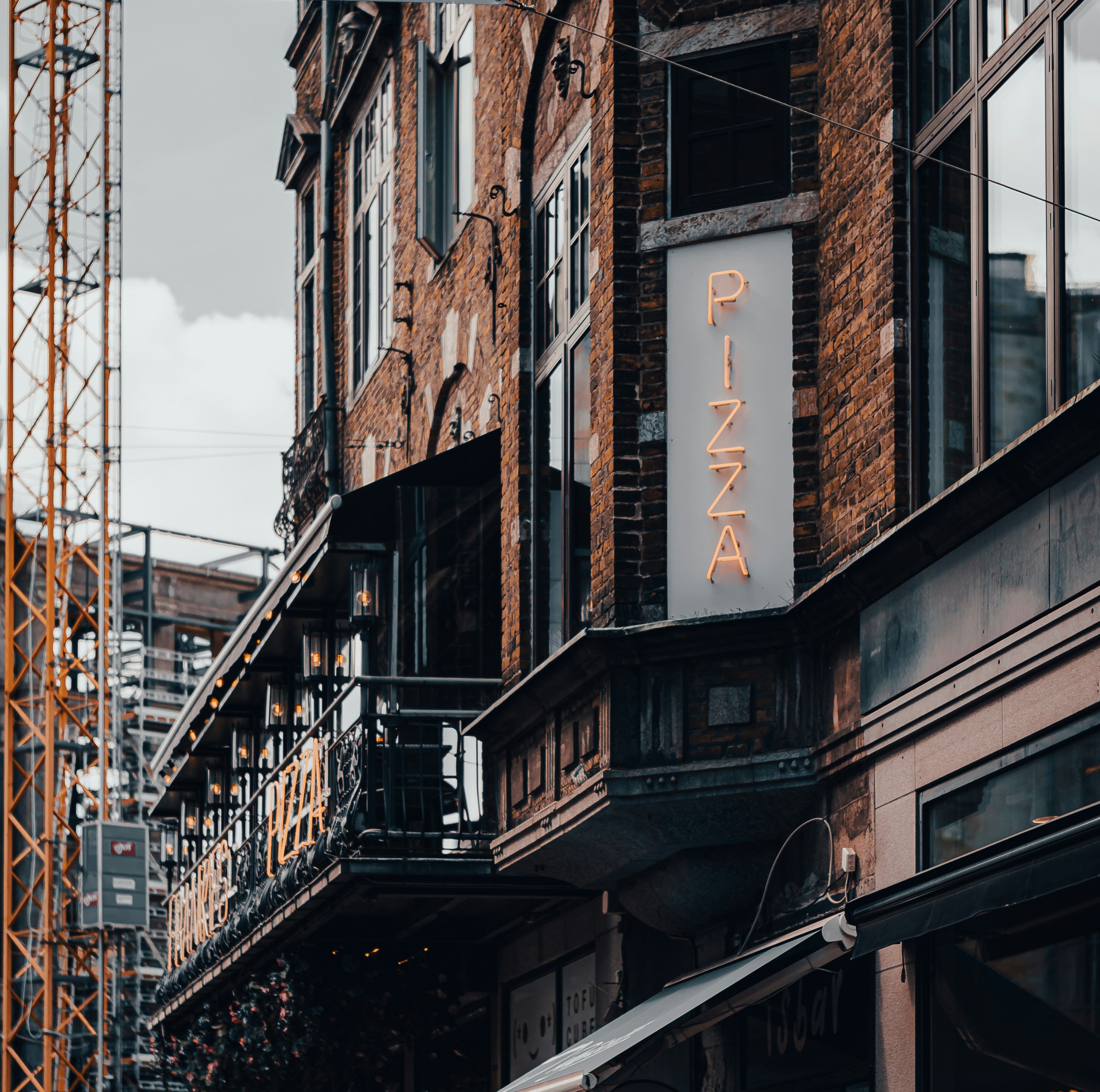 Neon Pizza Sign Amid Brick Facades Along a City Alley