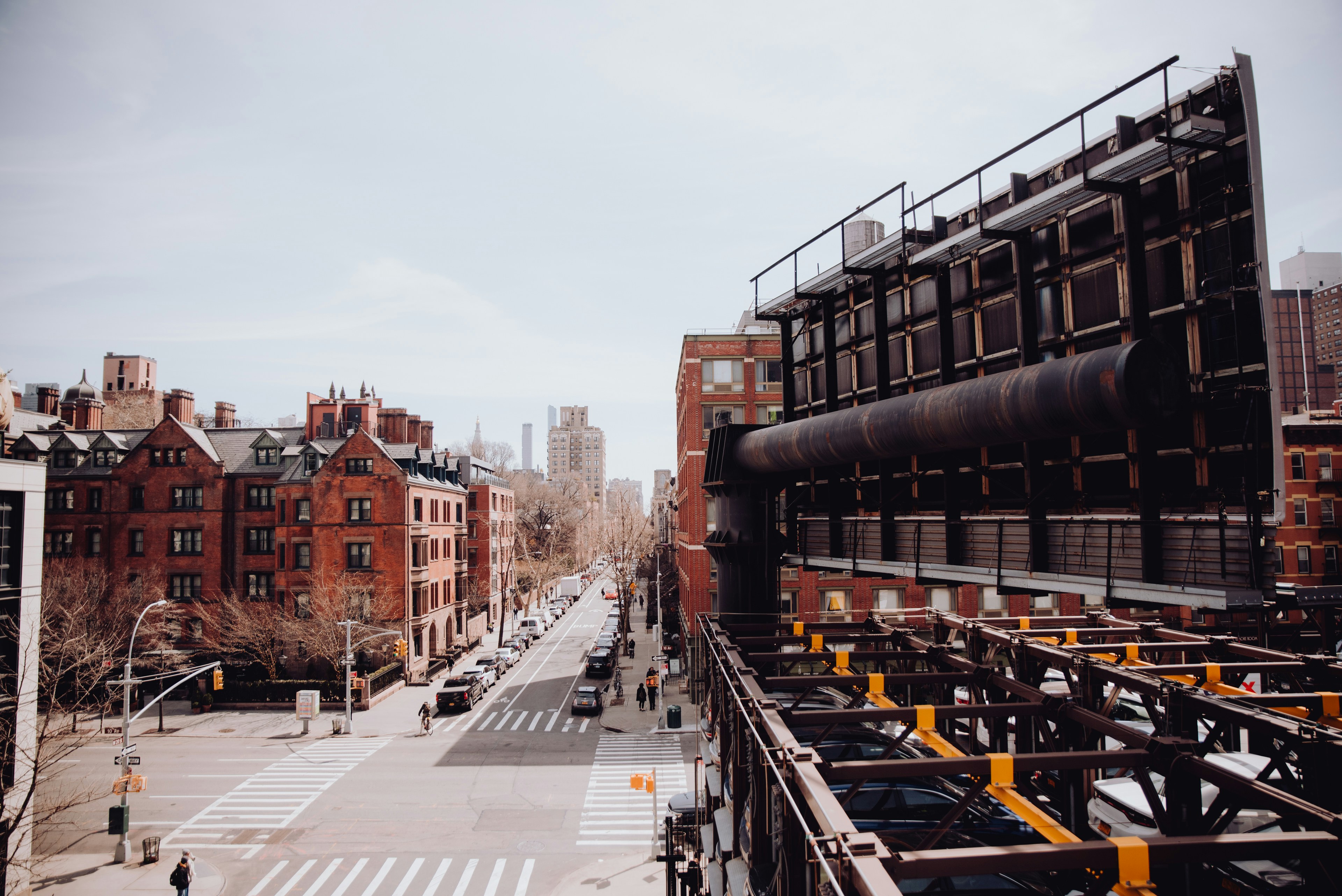 Aerial view of a New York street flanked by brick buildings and industrial structures under a clear sky.