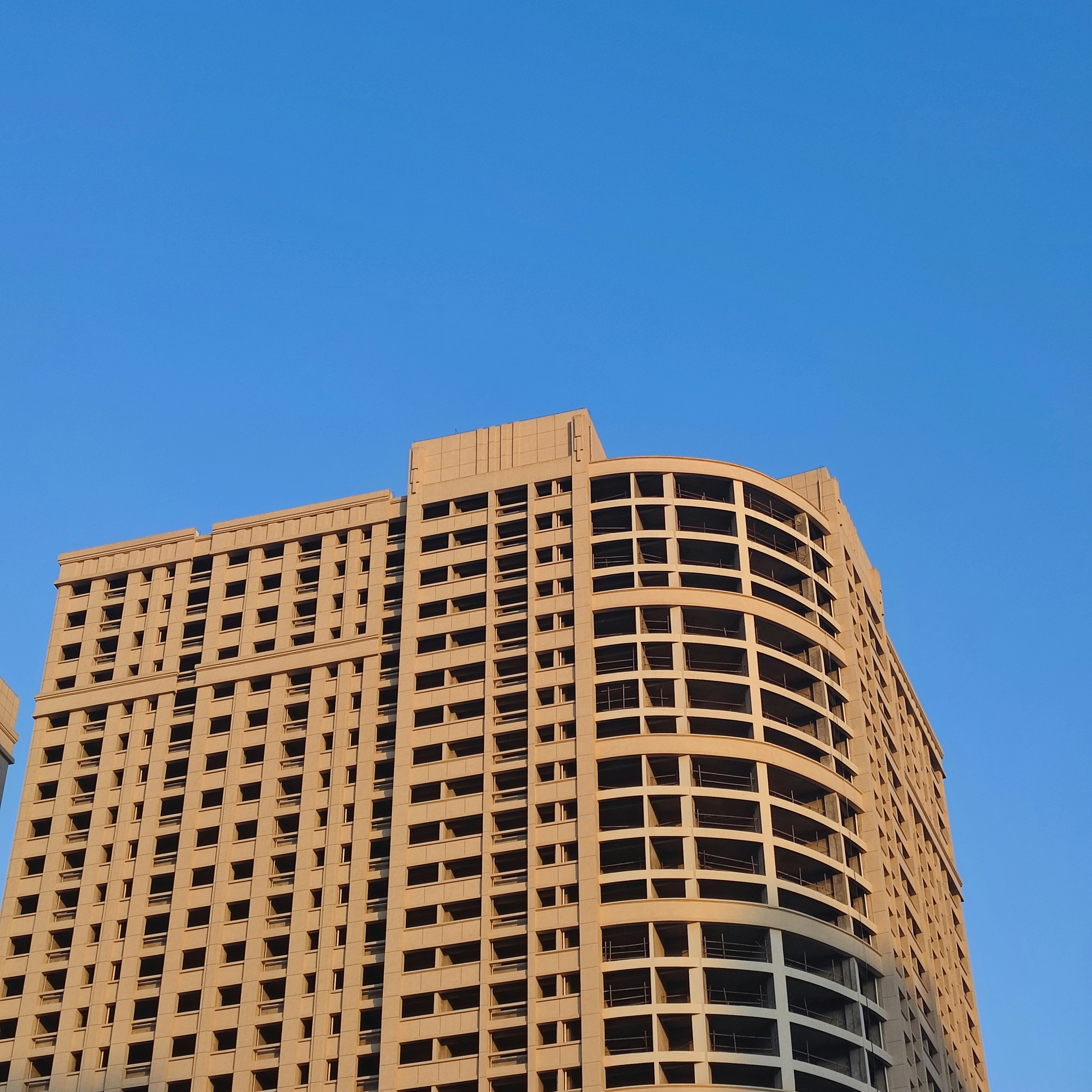 Modern high-rise building against a clear blue sky, showcasing unique architectural features and lines.