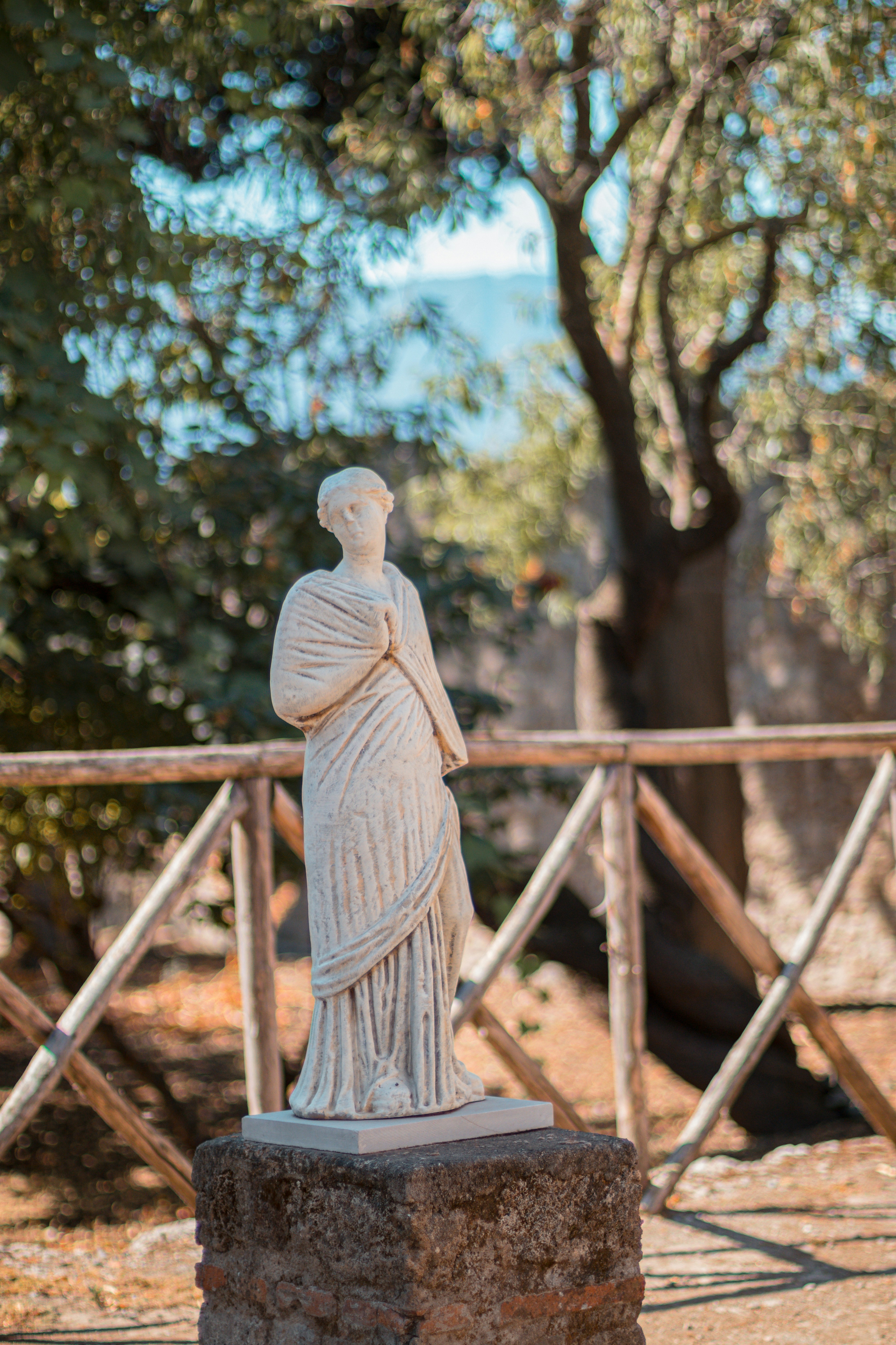 Sunlit Marble Sentinel Stands Beside Weathered Garden Rails