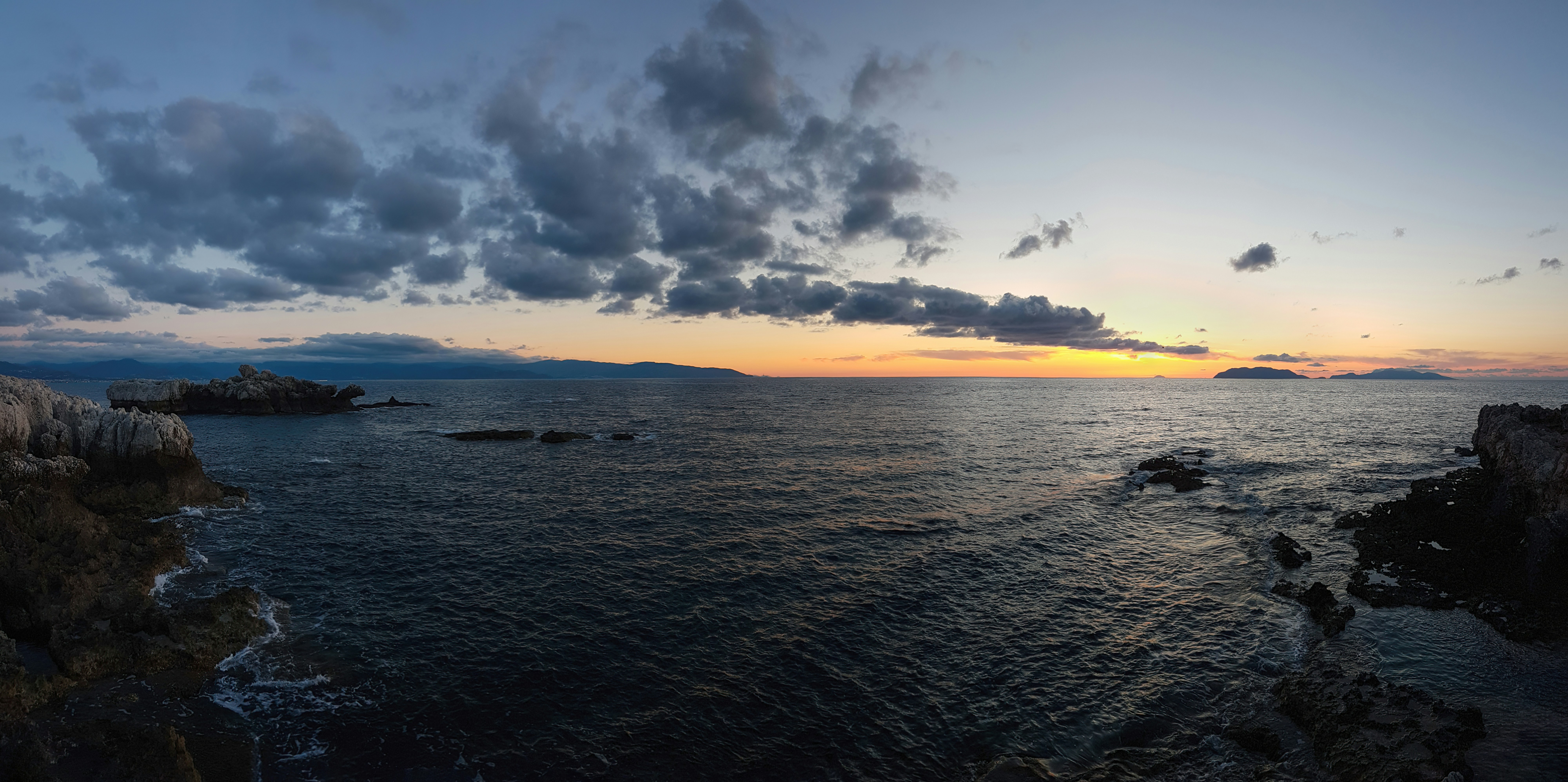 Expansive ocean view under a twilight sky with scattered clouds and distant horizon.