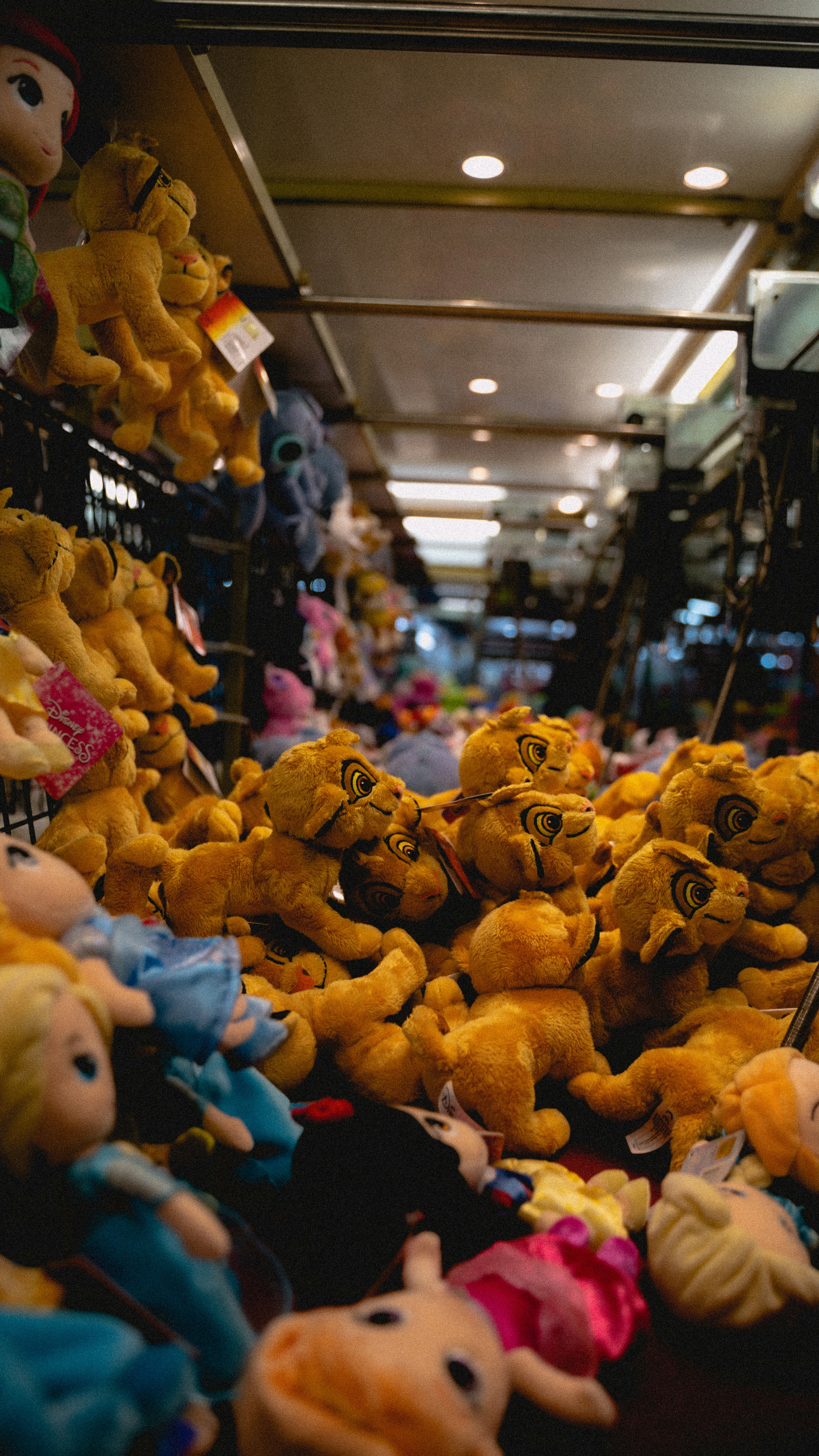 Vibrant collection of plush toys, including yellow lions and various characters, filling a lively market stall.