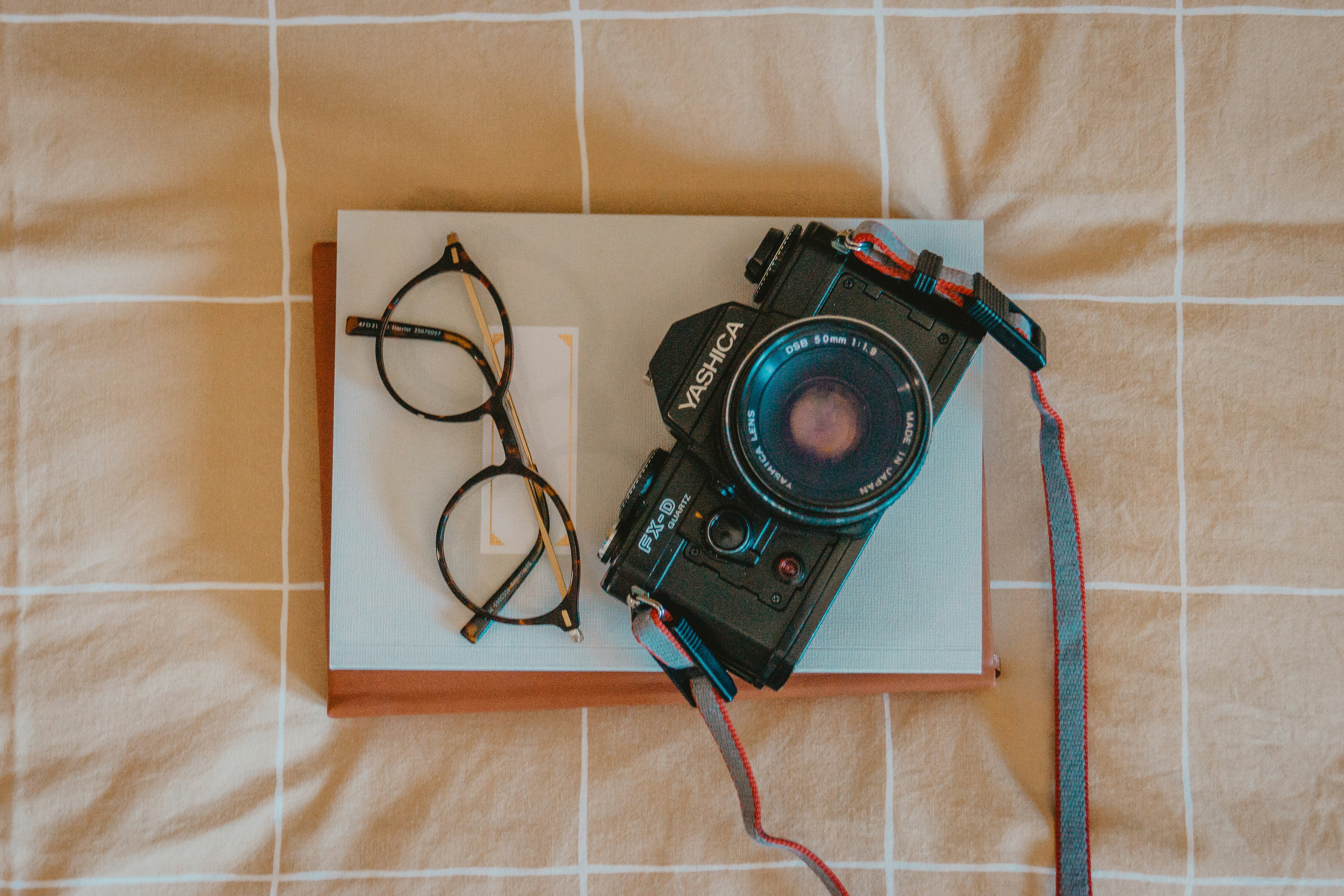 Vintage camera resting on a wooden surface beside round glasses, evoking a sense of creativity and exploration.
