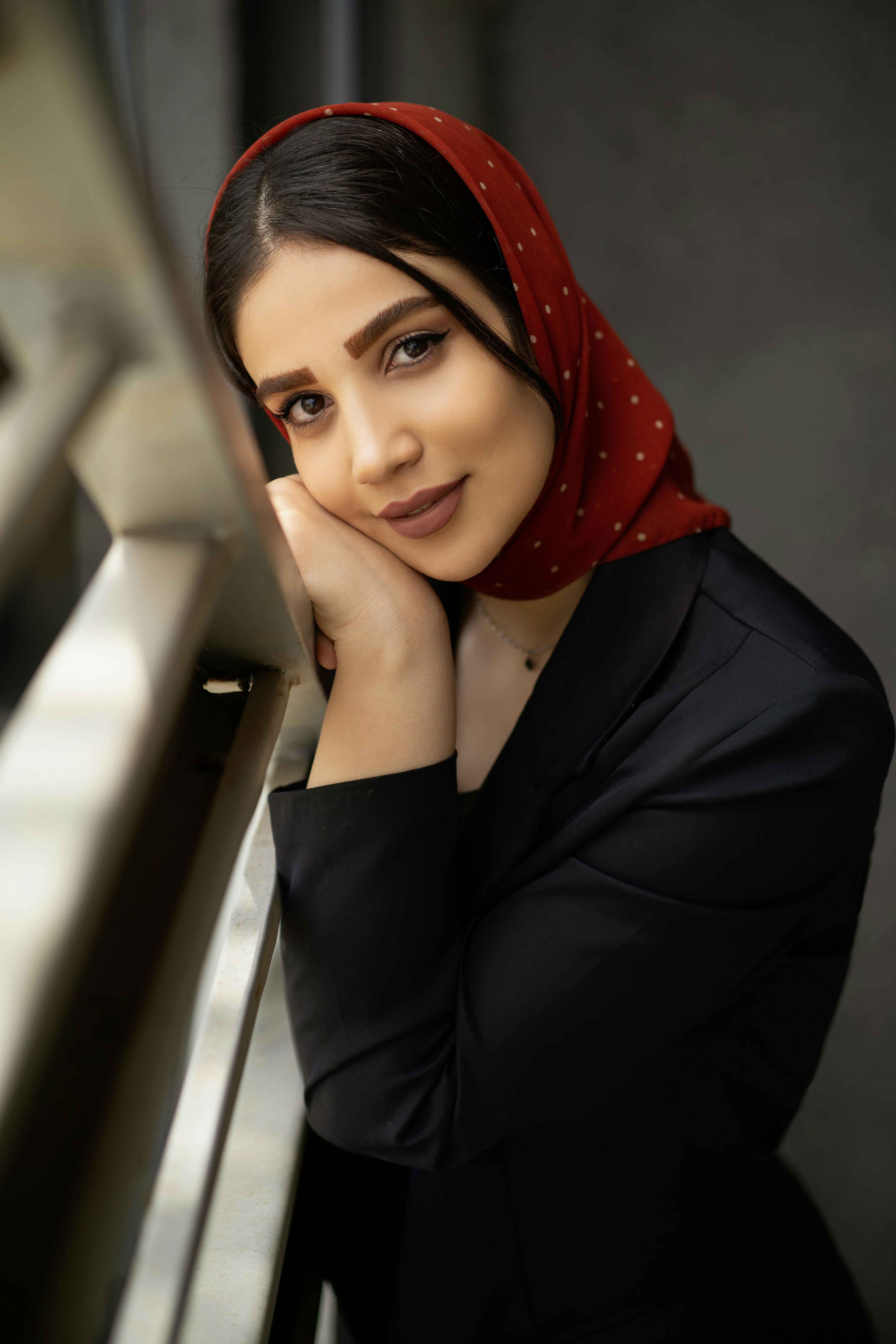 Soft Gaze by the Balcony Rail: Portrait of a Woman in a Red Hijab
