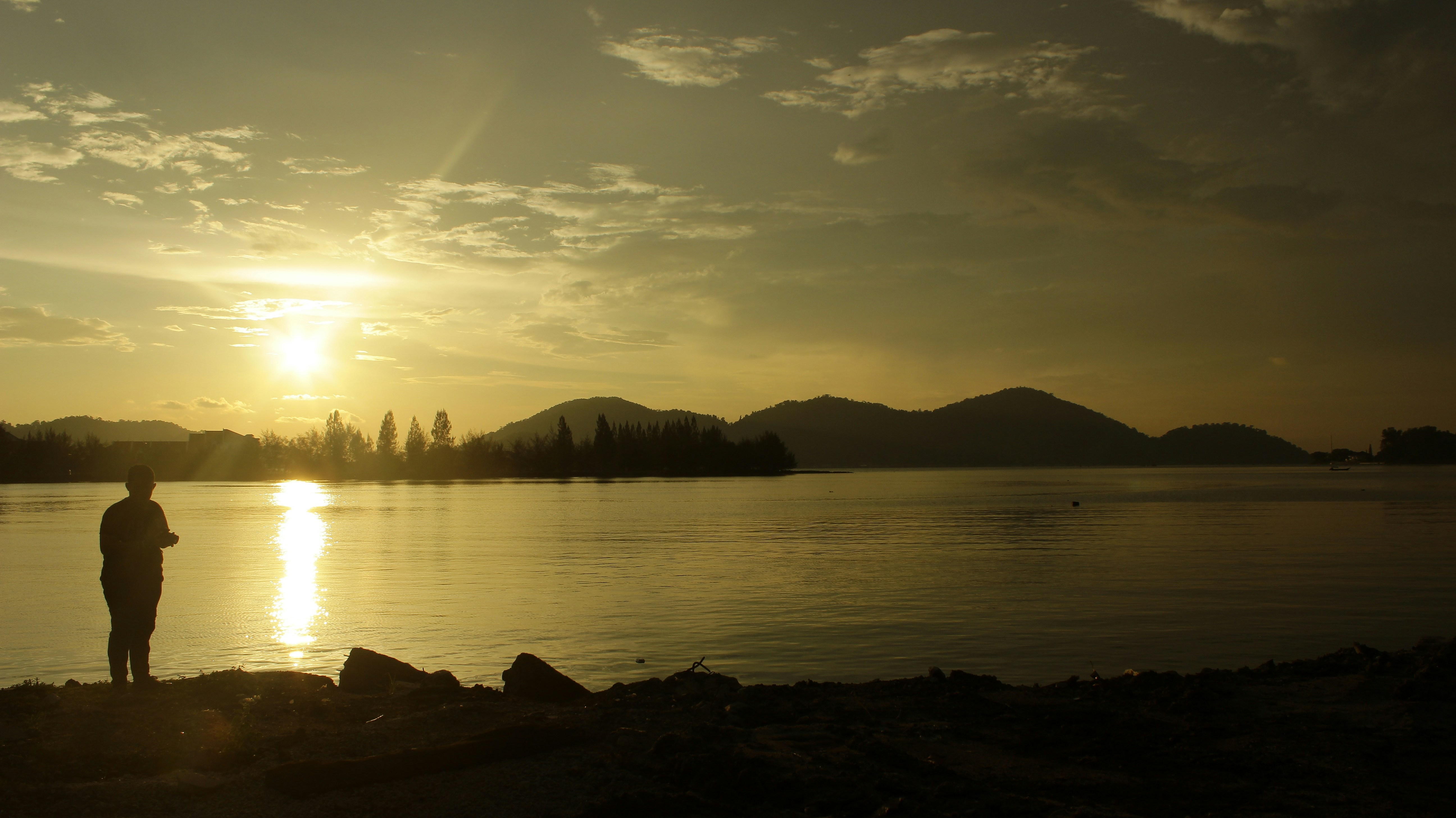Silhouette by the Shore: Sunset Over Quiet Water