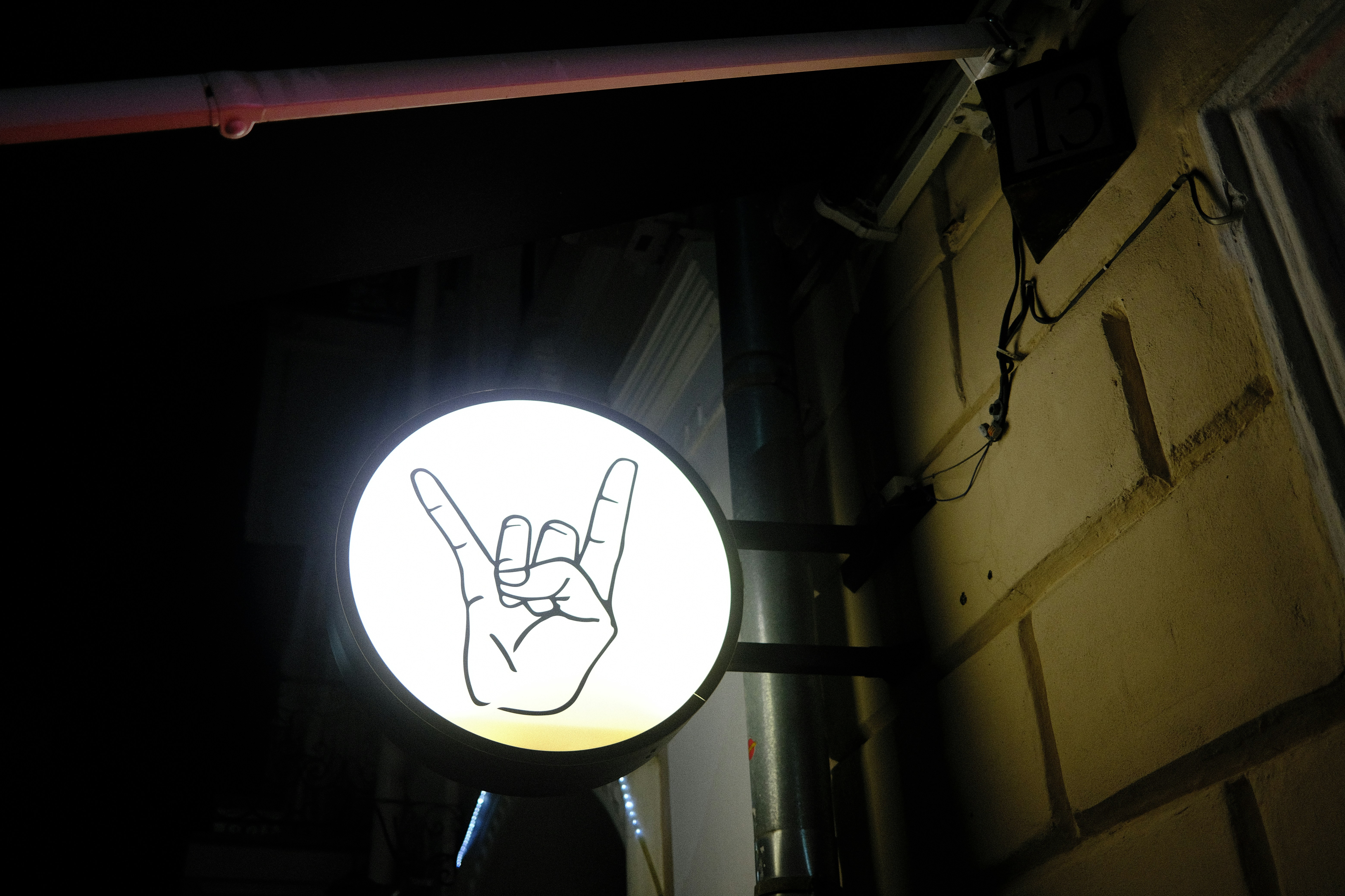 Circular light fixture on a wall featuring a hand making the rock gesture.
