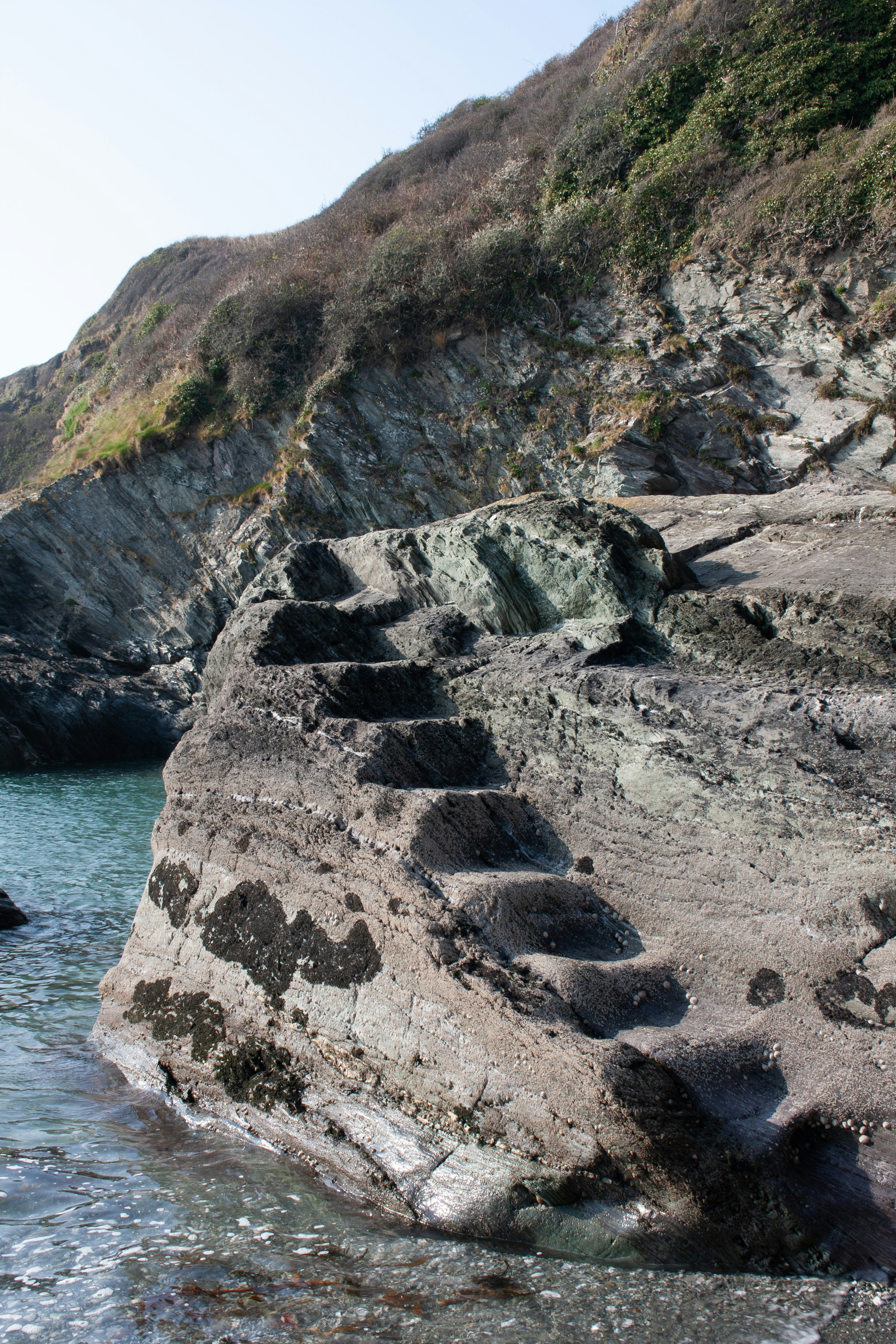 A rocky cliff next to the water photo – Free Grey Image on Unsplash