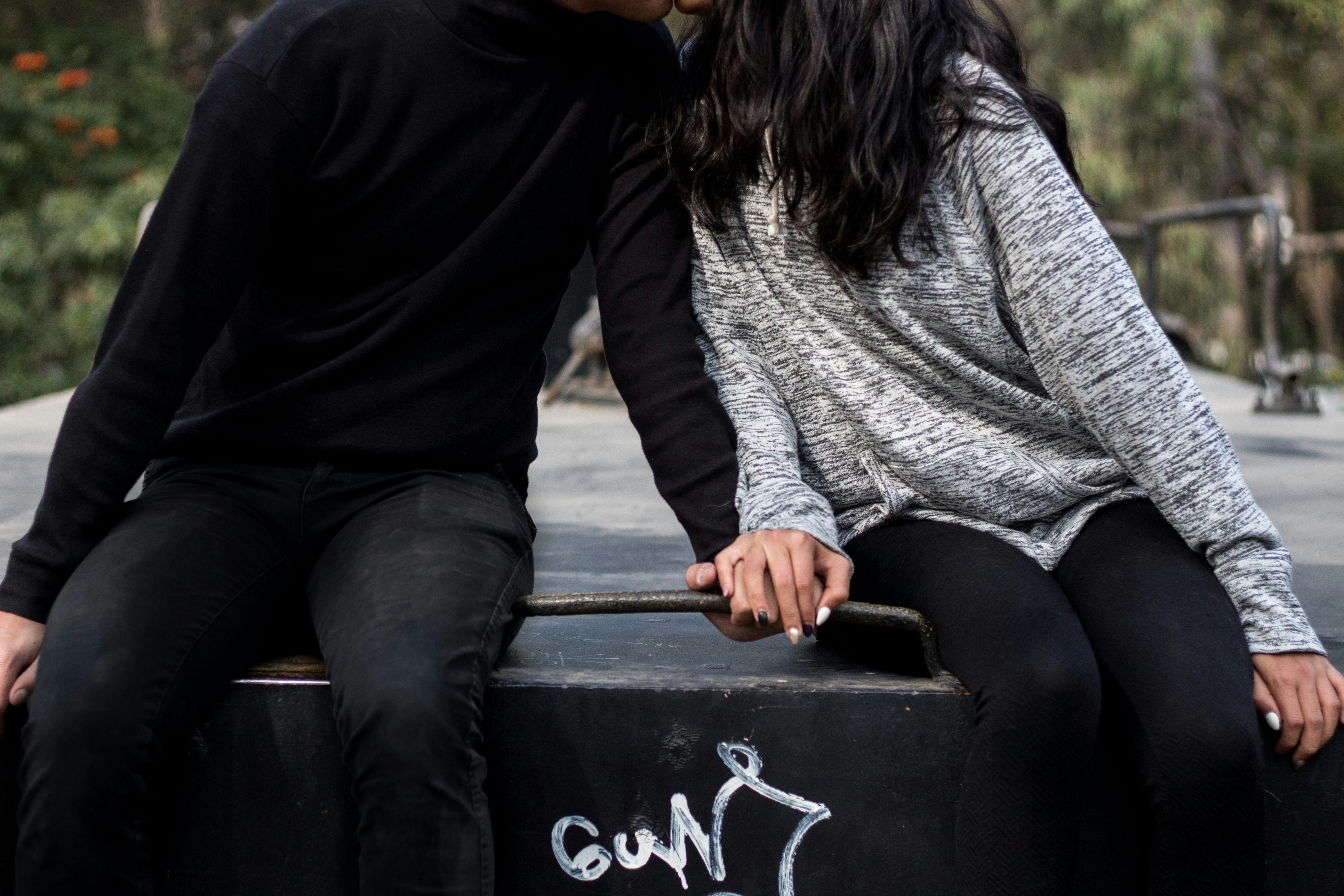Holding On: A Quiet Moment of Connection on a Graffiti-Softened Urban Bench