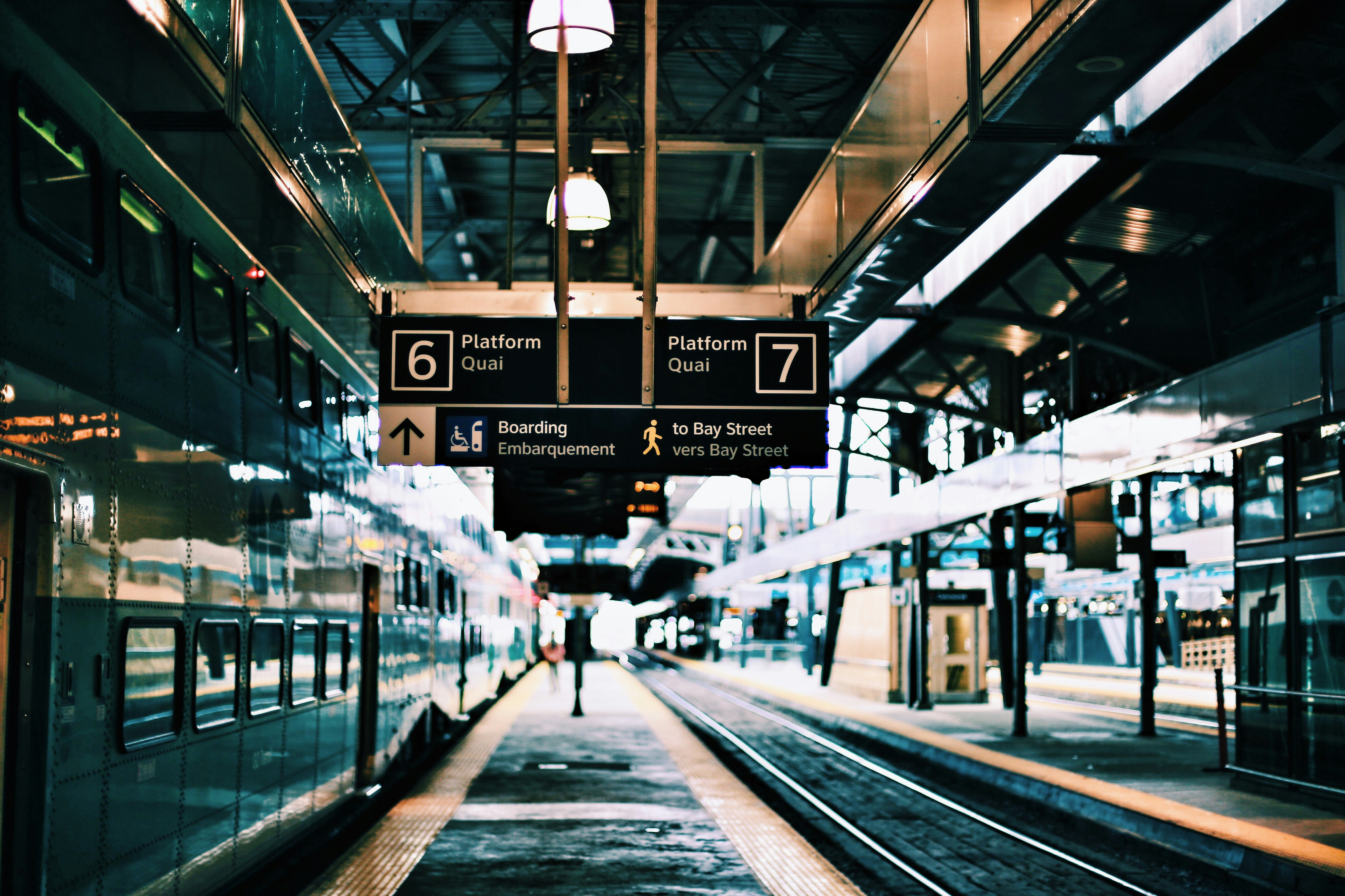 Train station platform with signs indicating platforms 6 and 7, featuring a traveler in the distance. The scene captures the essence of transit and movement.