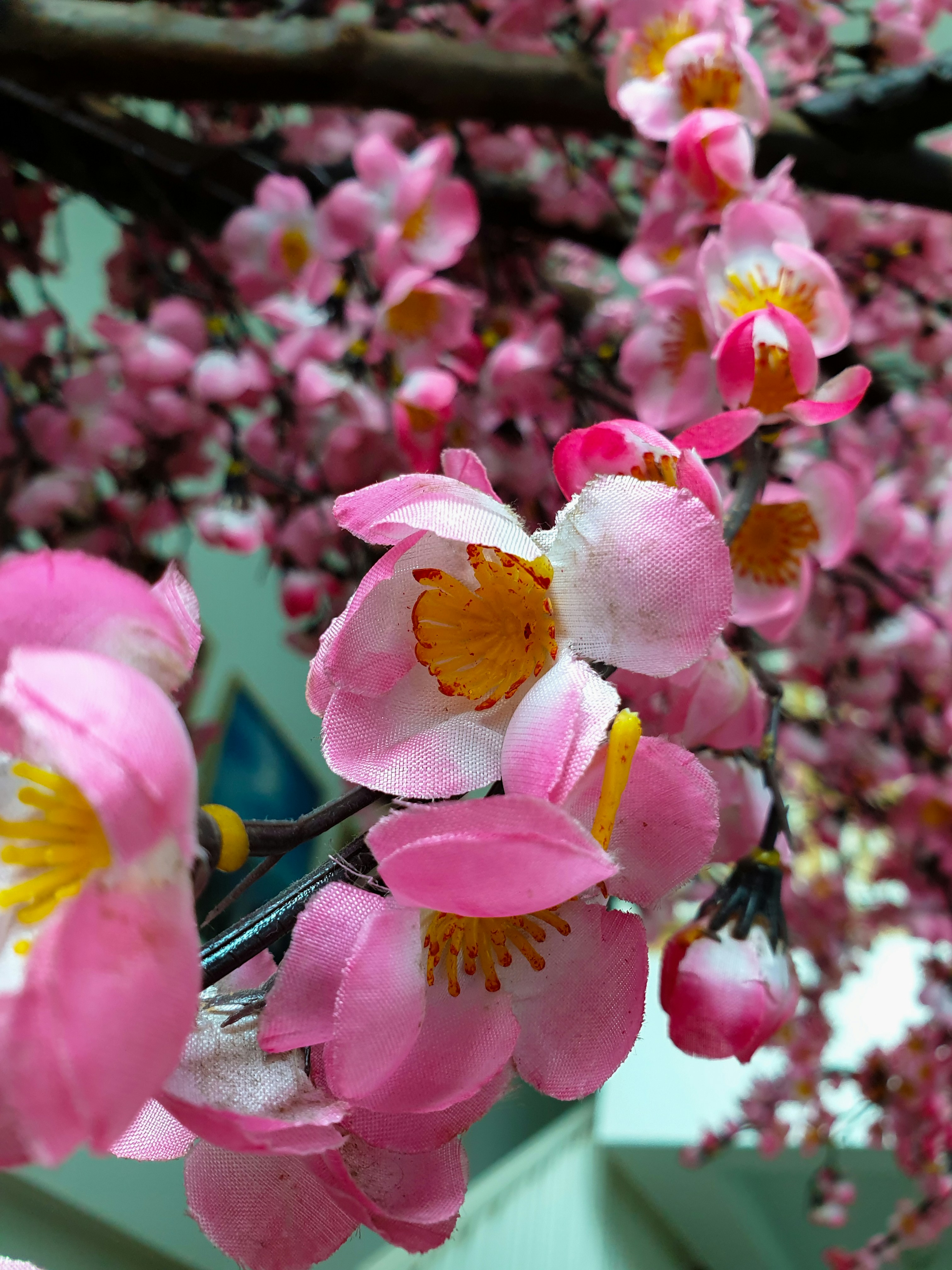 Delicate pink blossoms with vibrant yellow centers, capturing the essence of artificial spring blooms against a softly blurred background.
