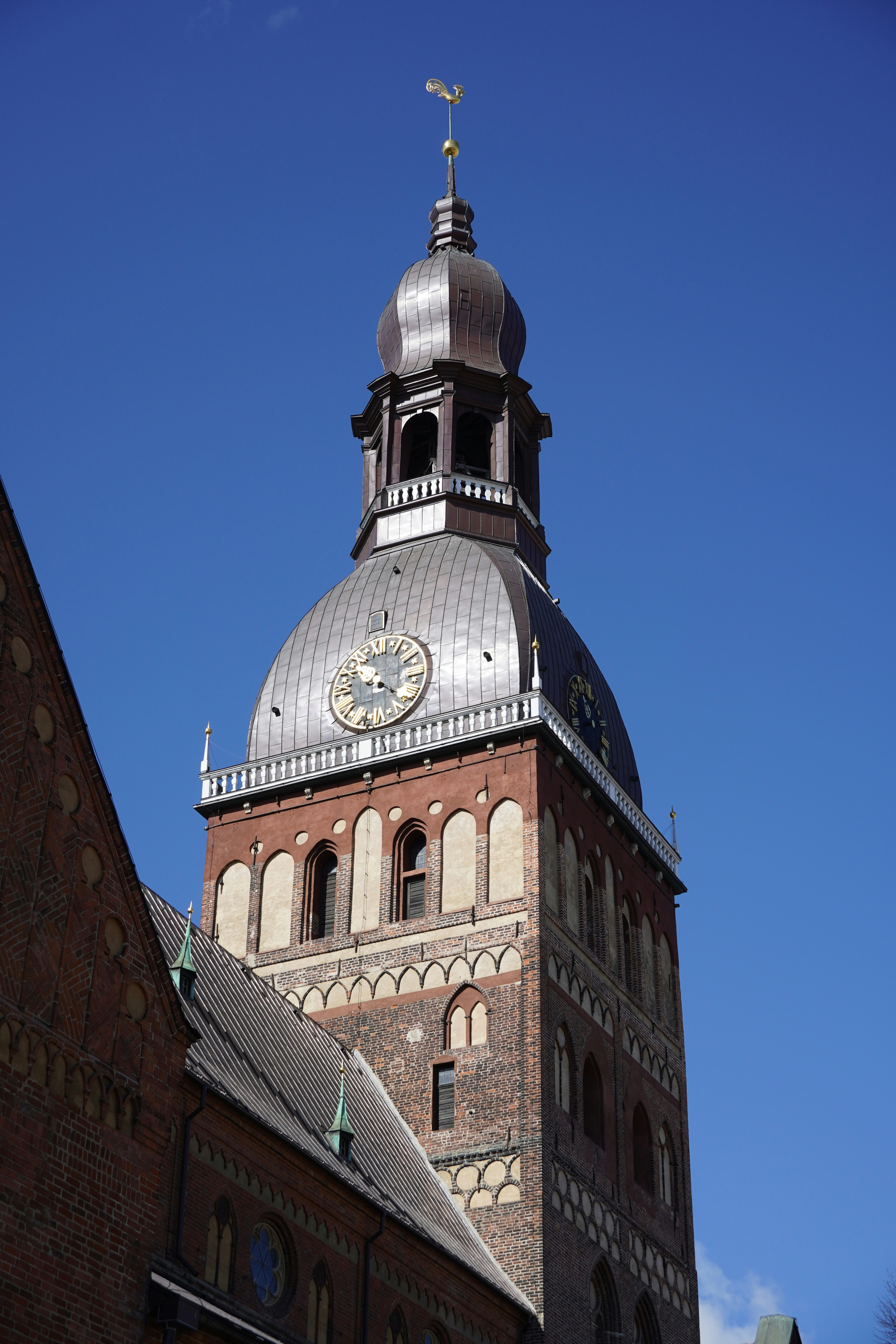 Historic clock tower with a copper dome and intricate details against a clear blue sky.