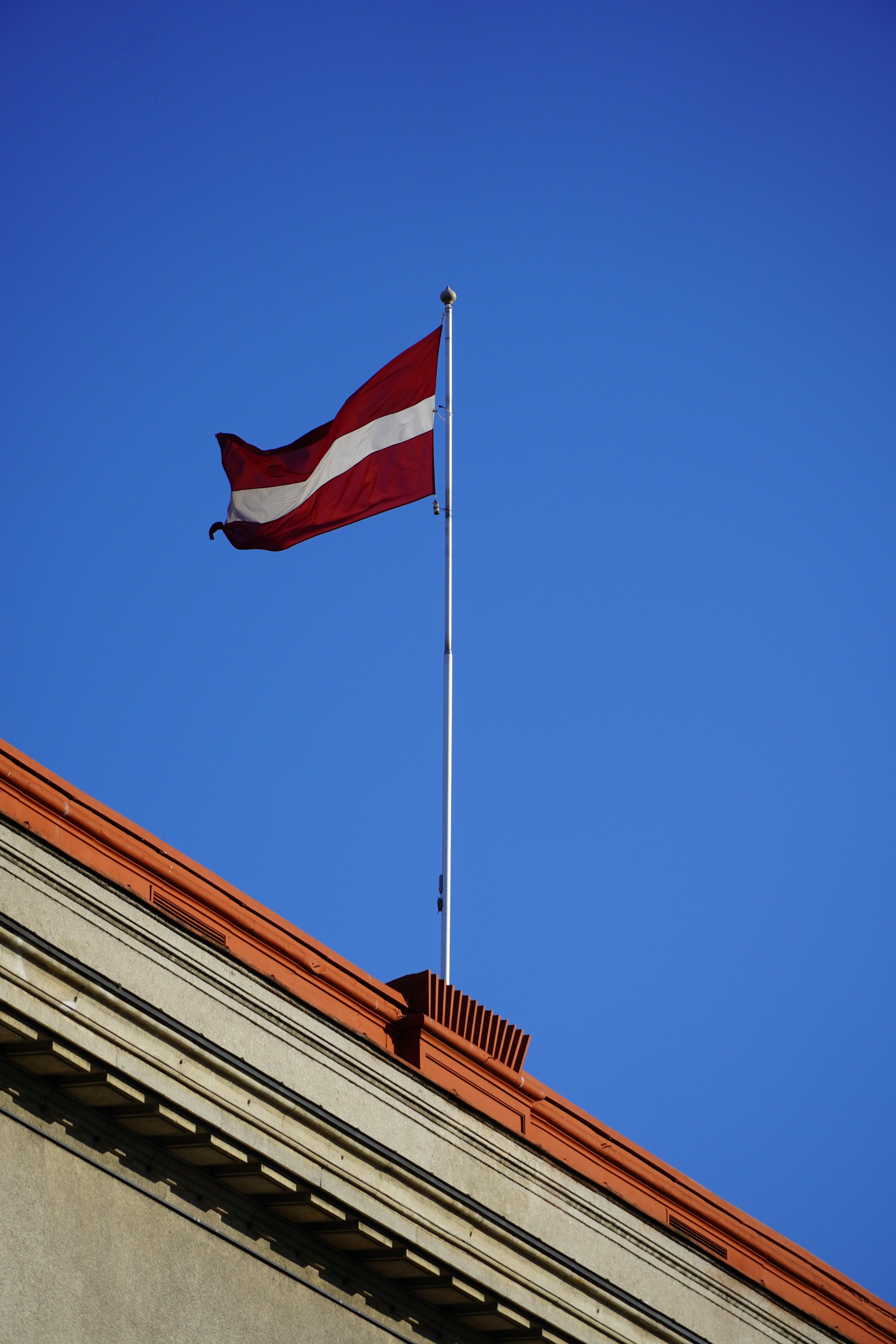 Flag Over the Ridge: A Red-White Banner Against a Pristine Sky