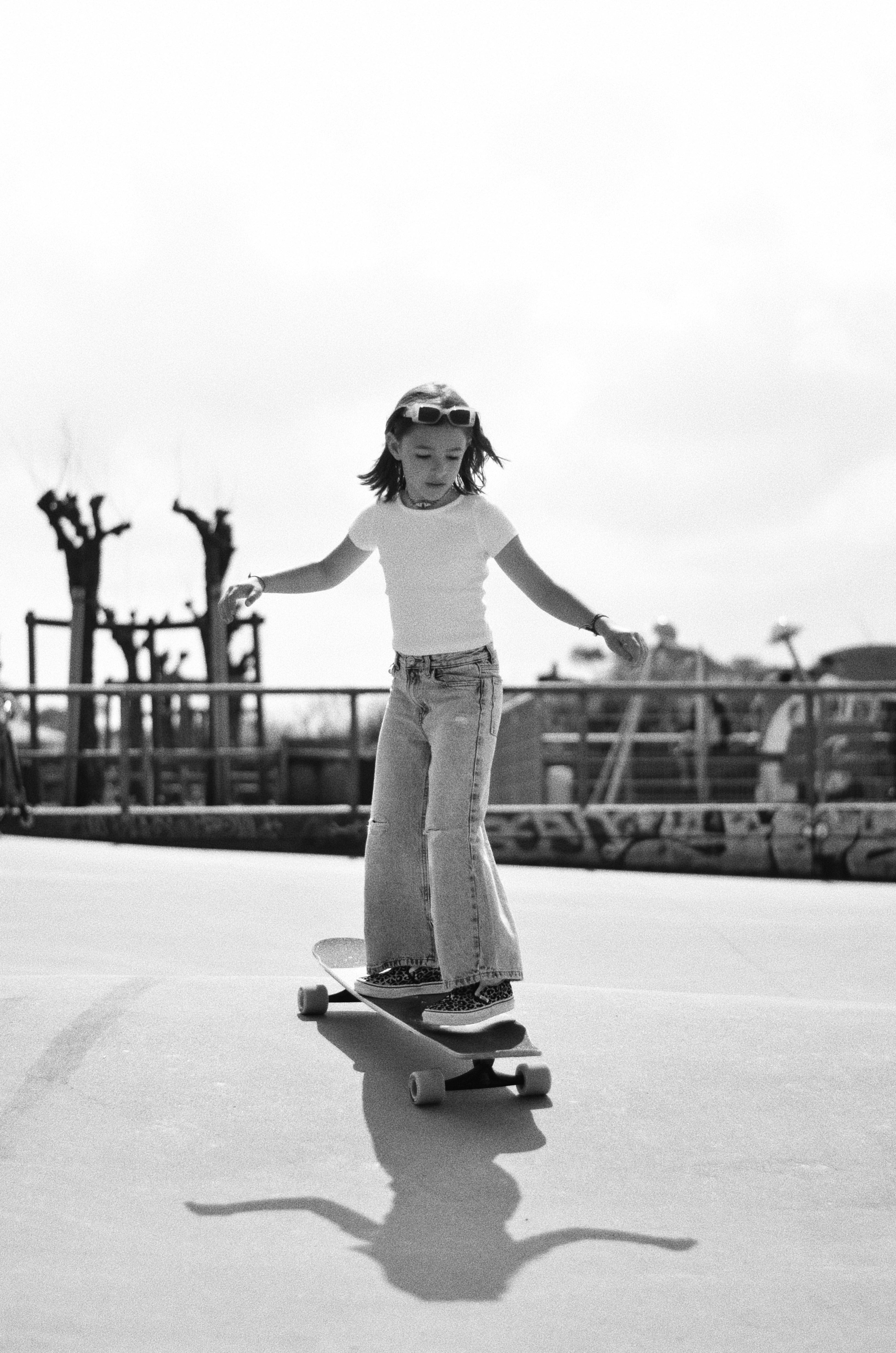 Young skateboarder navigating a skate park with confidence, casting a playful shadow on the ground.