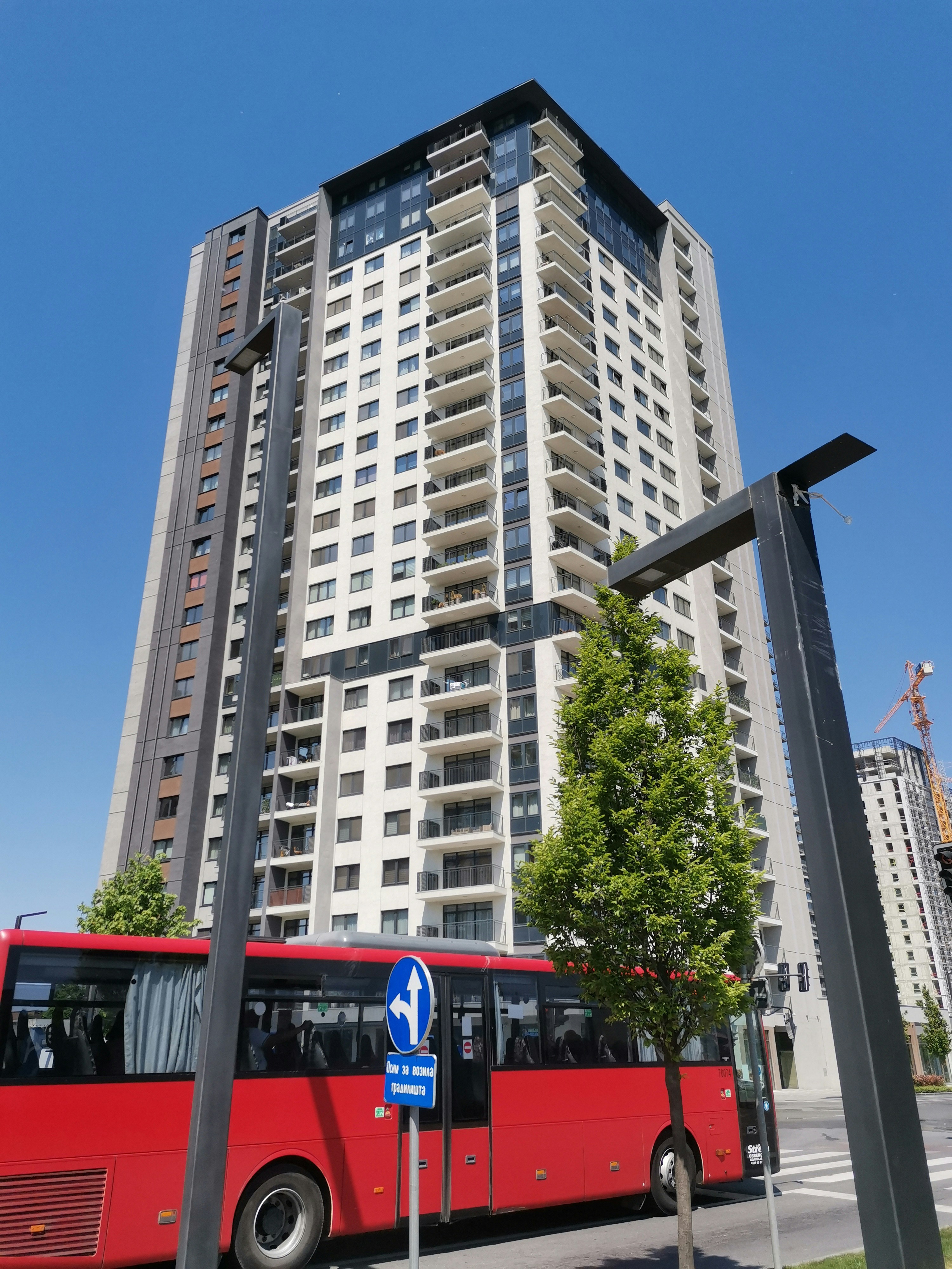 Towering Red Bus Stop: A Modern High-Rrise Framed by City Sculpture