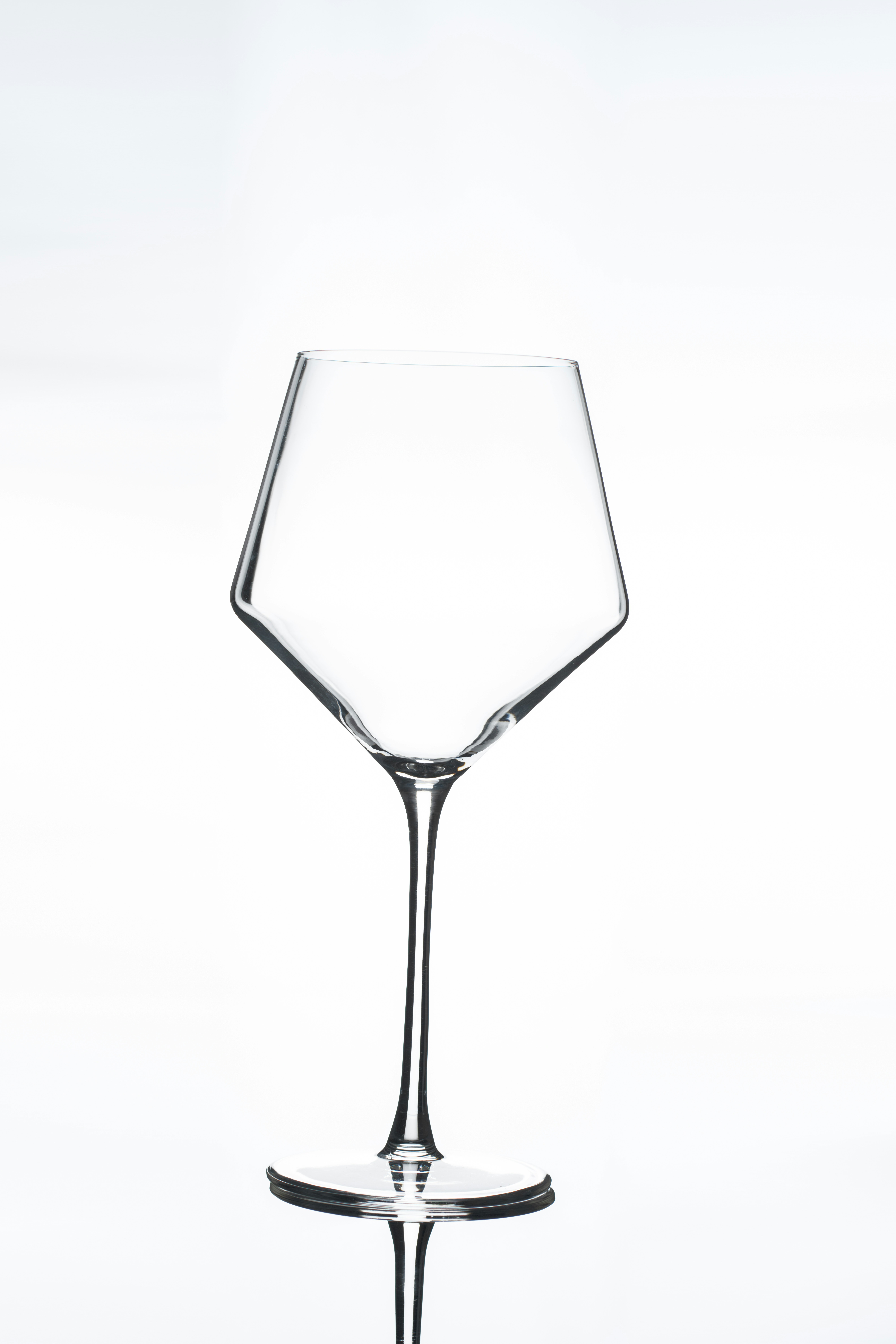 A minimalist depiction of a uniquely shaped wine glass against a soft white background.