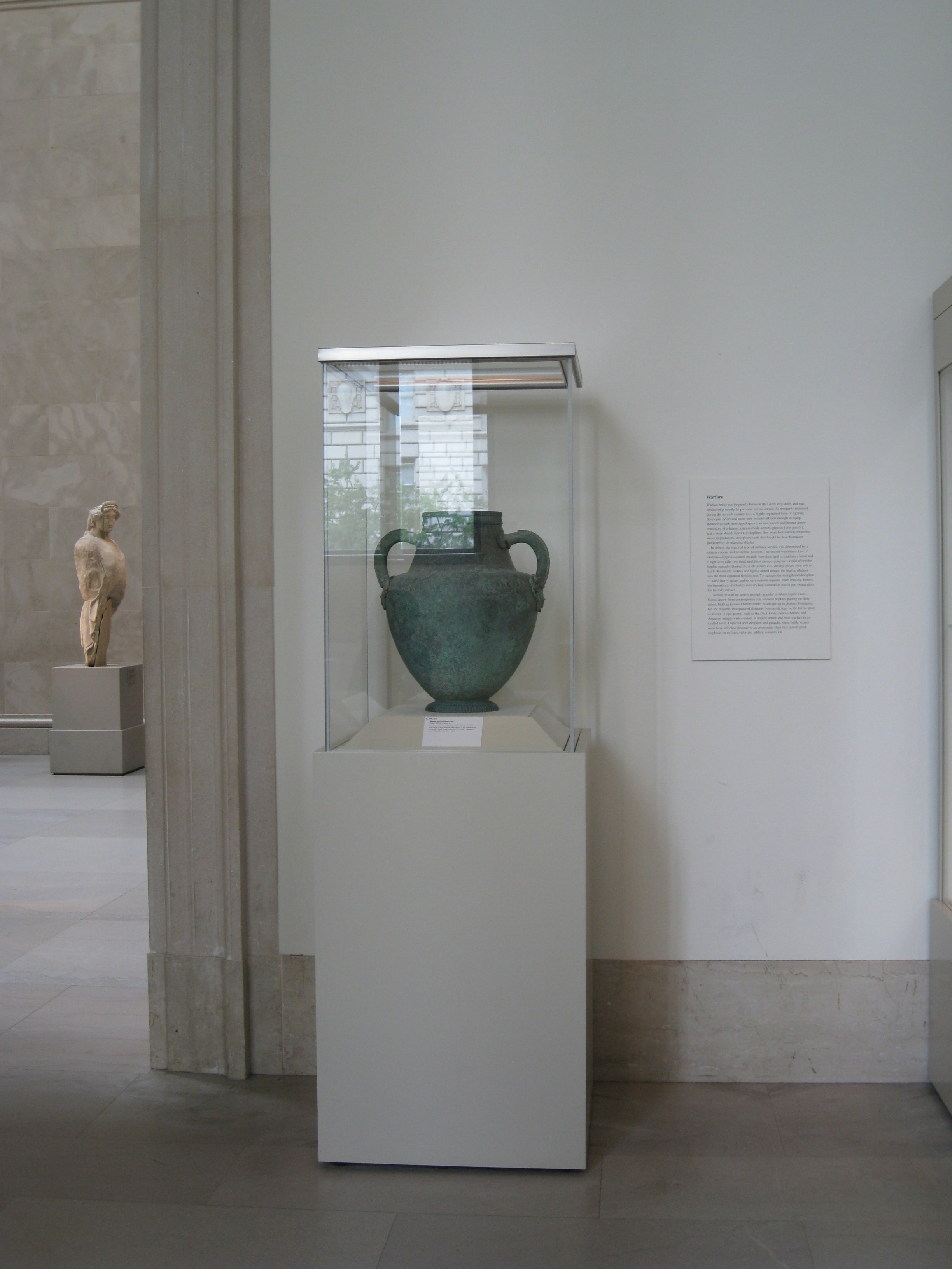 Bronze amphora displayed in a glass case within an art museum, highlighting its intricate design and historical significance.