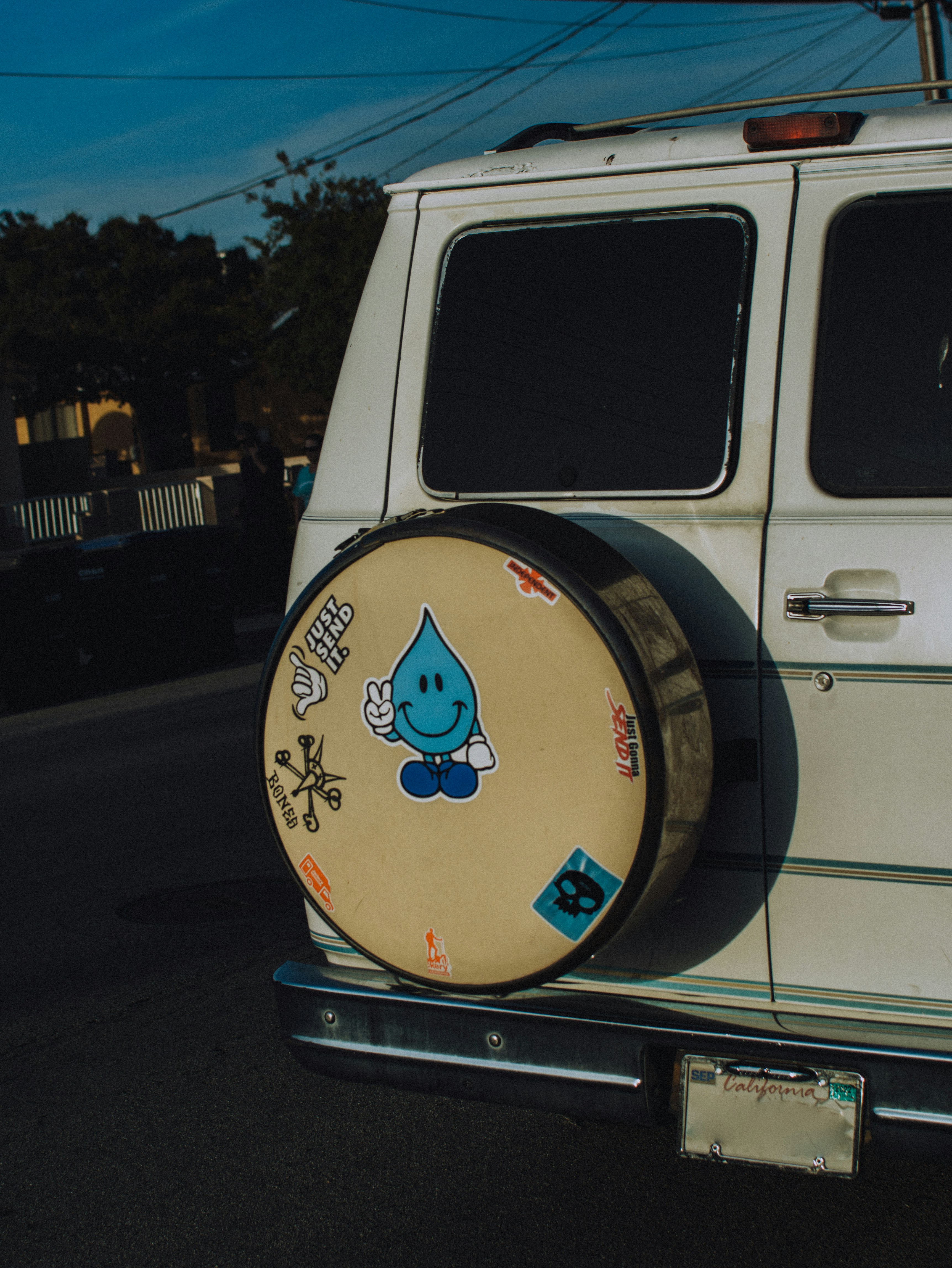 Blue Droplet Mascot on a Weathered Van's Rear Wheel Cover