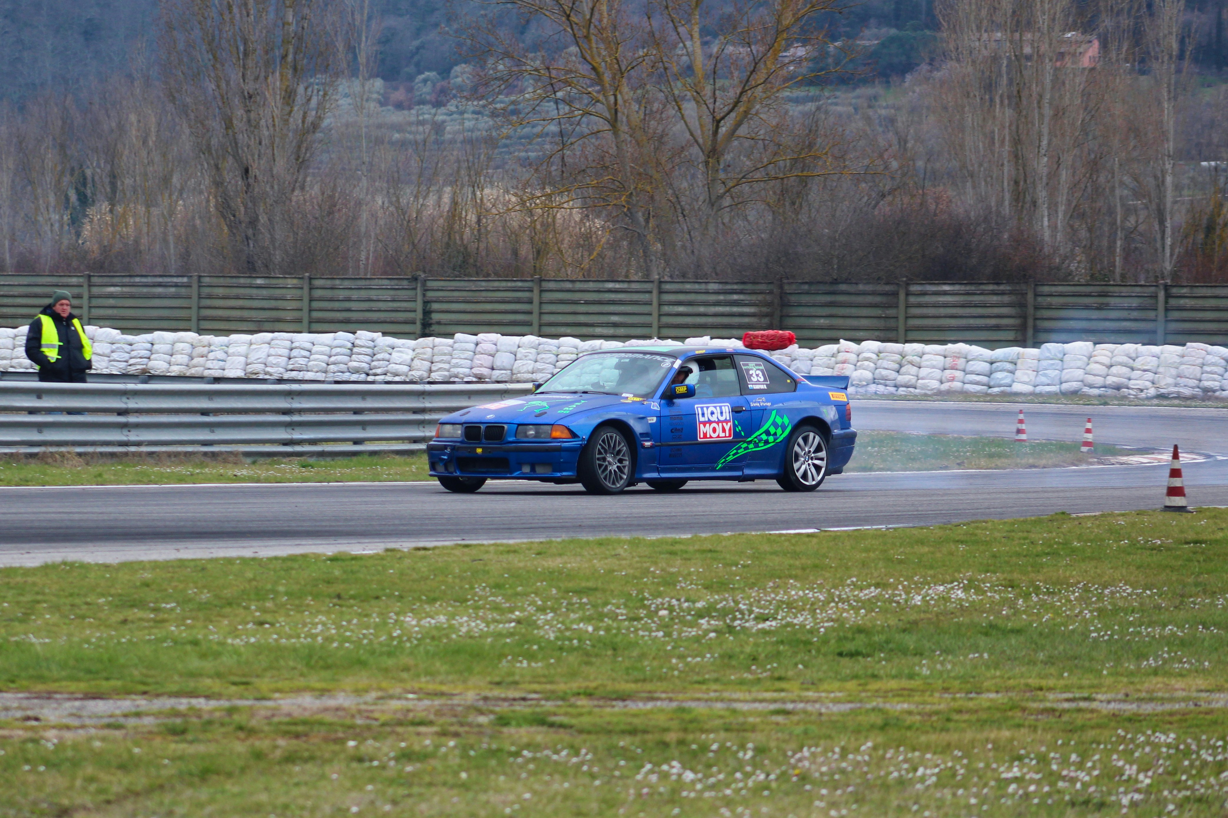 Blue sponsor-liveried rally car carves through a damp track with a winter backdrop