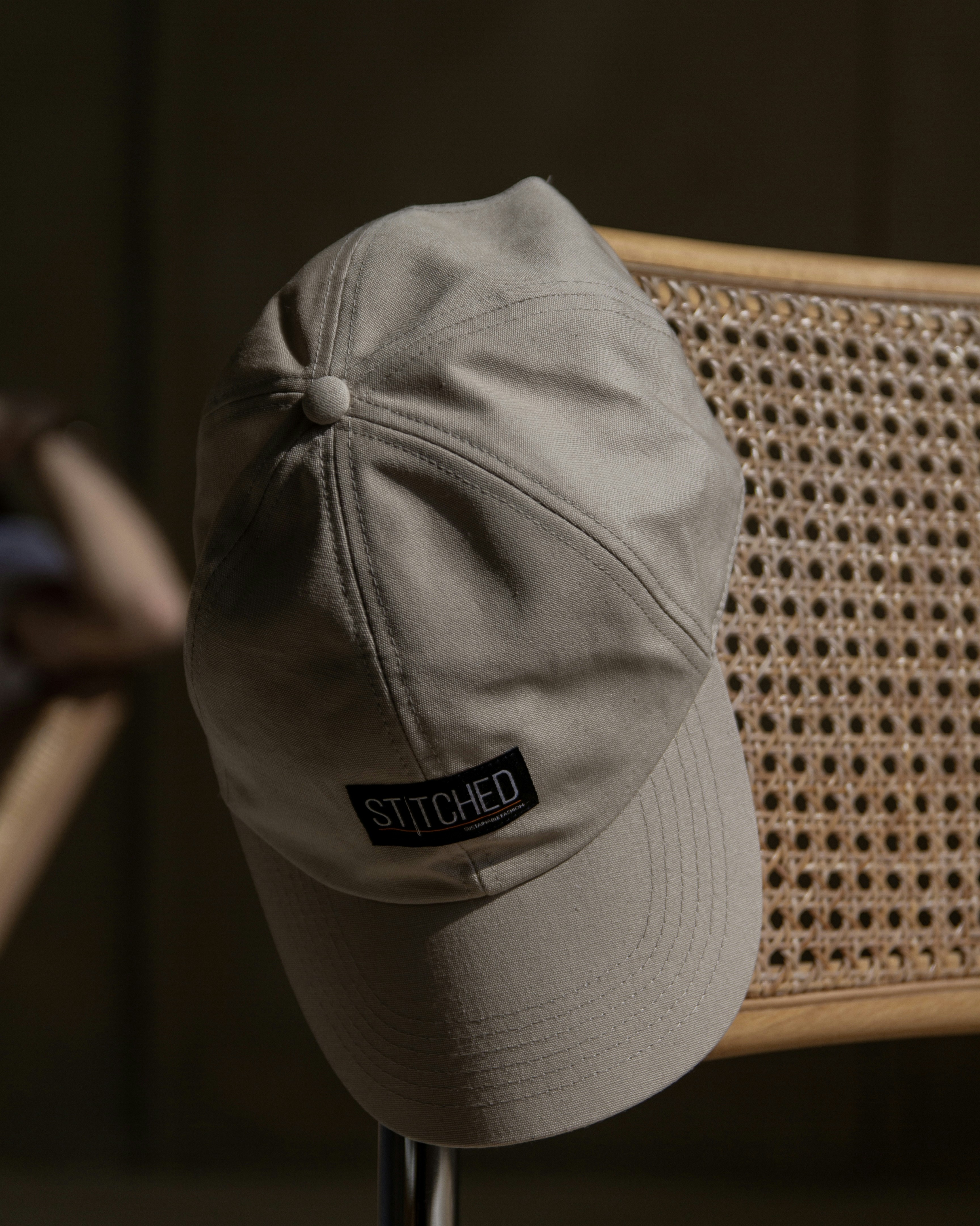 Stitched Beige Cap Framed by a Woven Cane Chair in Soft Studio Light