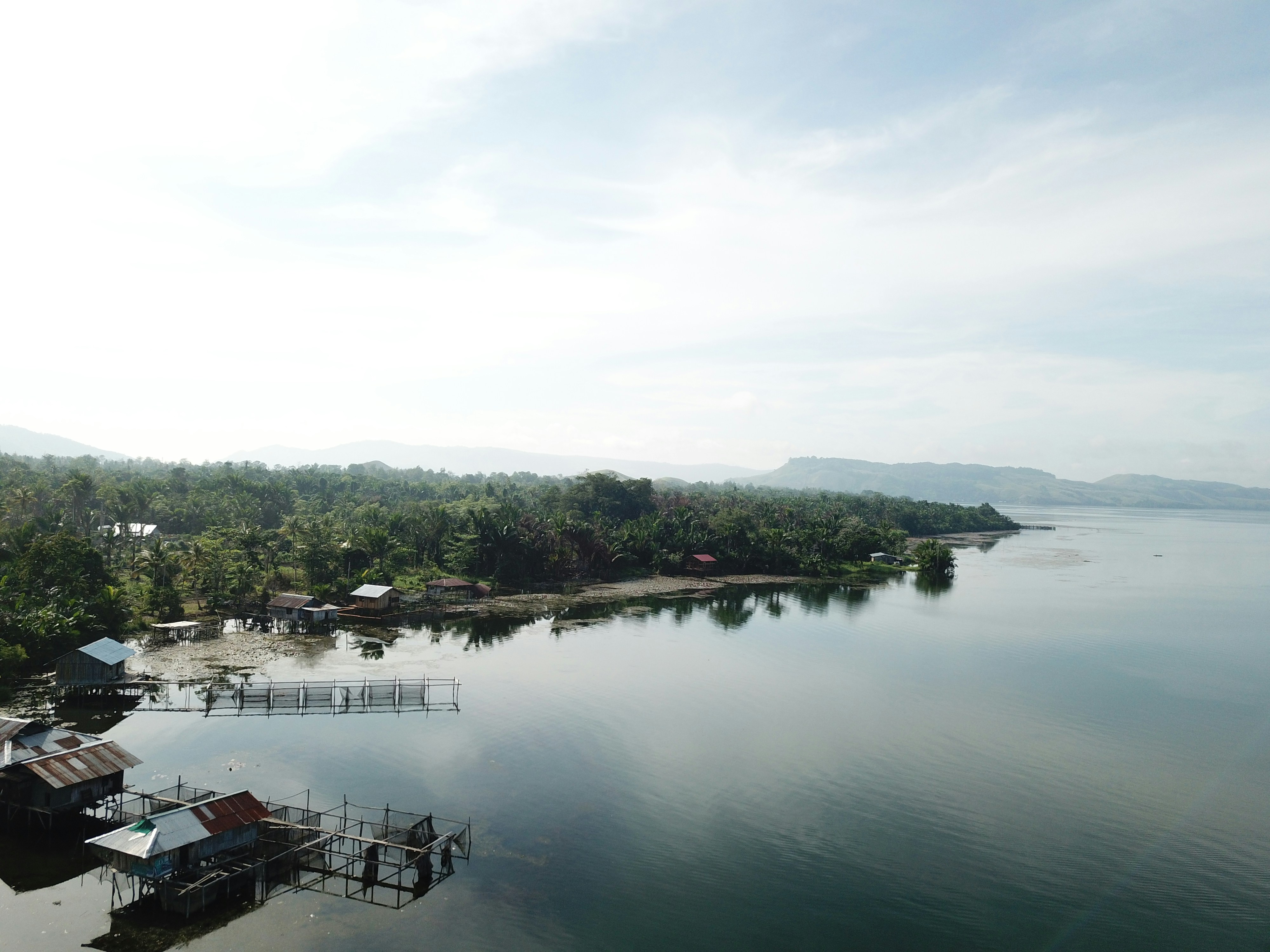 A body of water with buildings and trees around it photo – Free Sentani ...