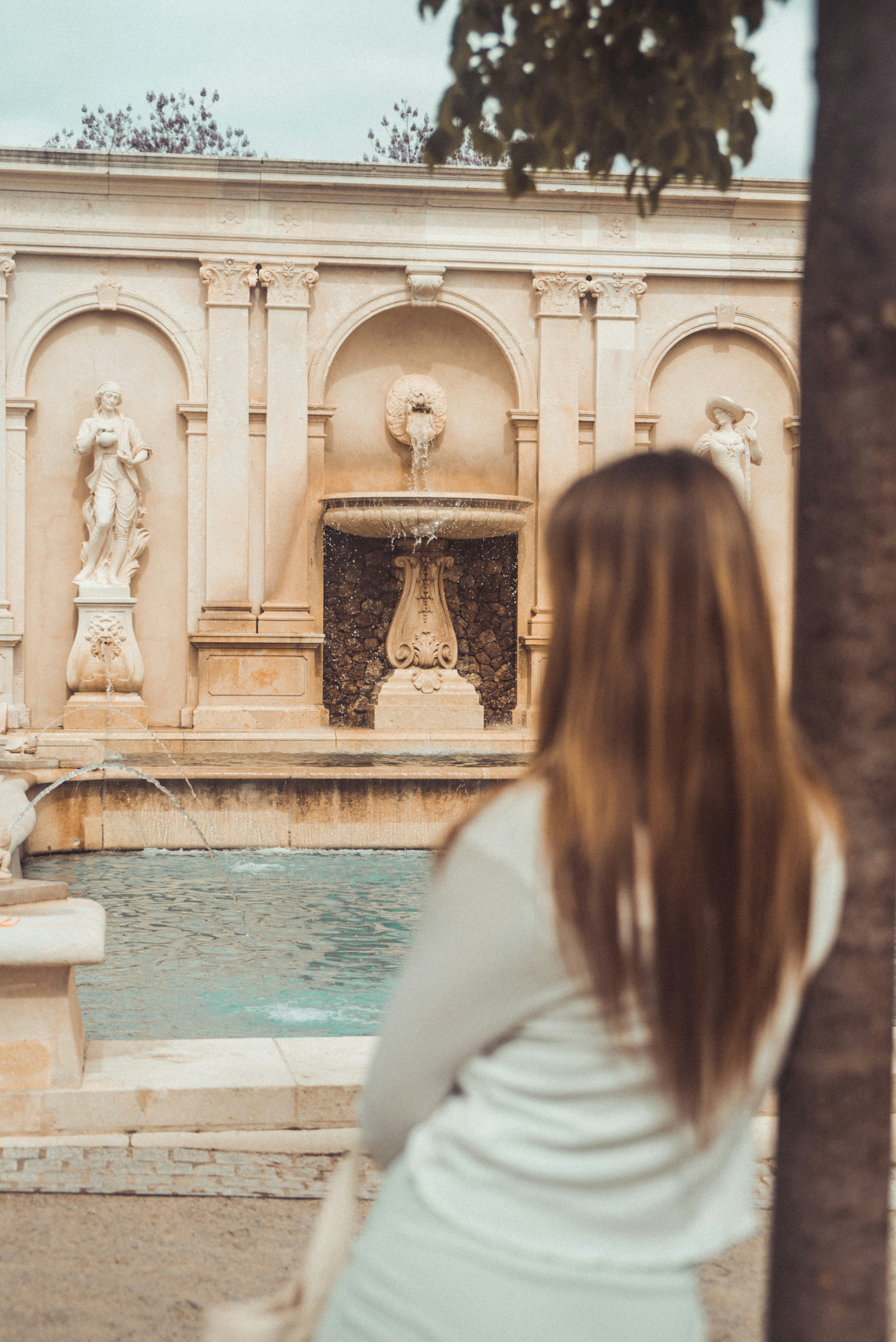 Turning Toward Marble: A Back View Framing a Classical Fountain