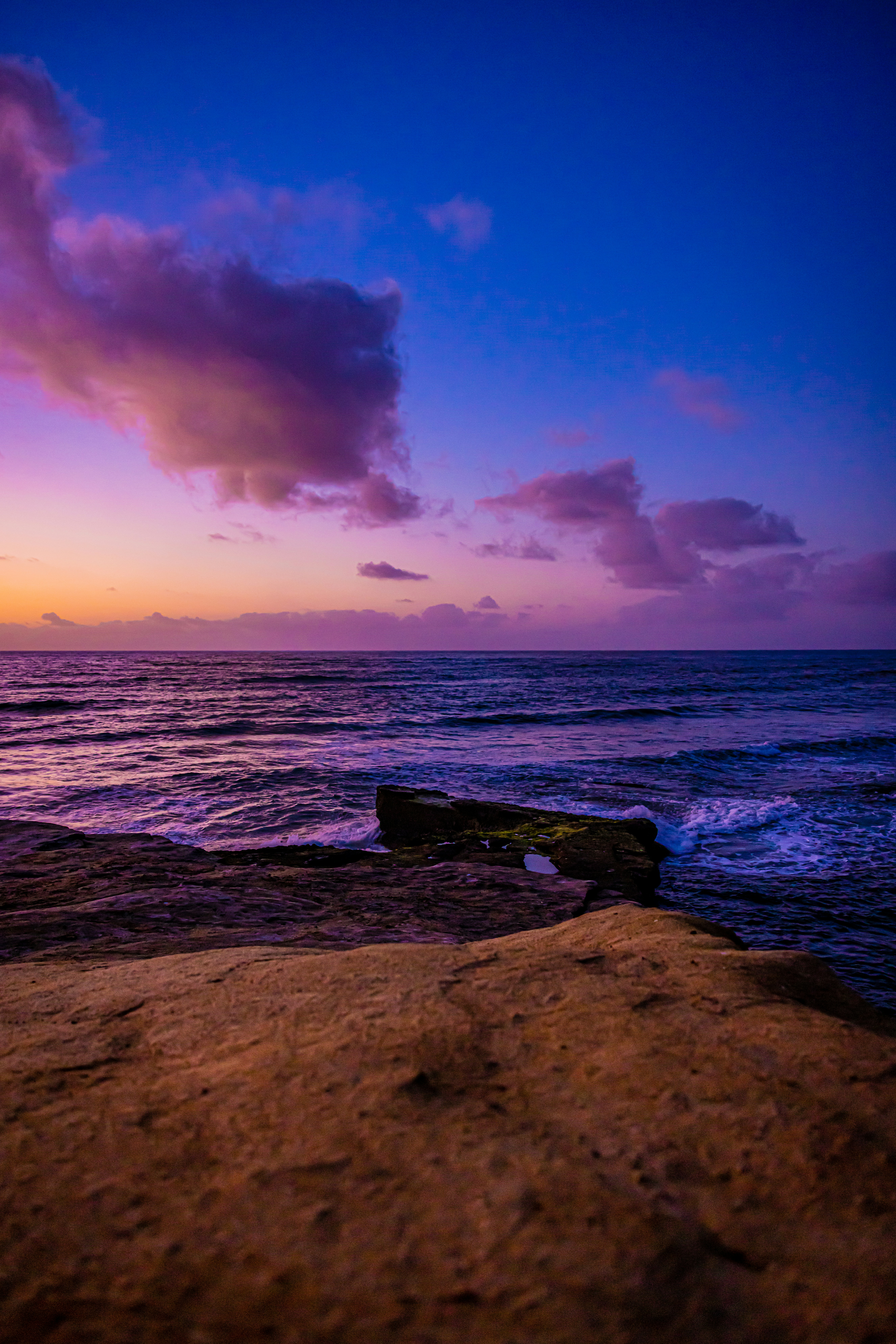 Foto Una playa con una roca en el agua y una puesta de sol – Imagen ...