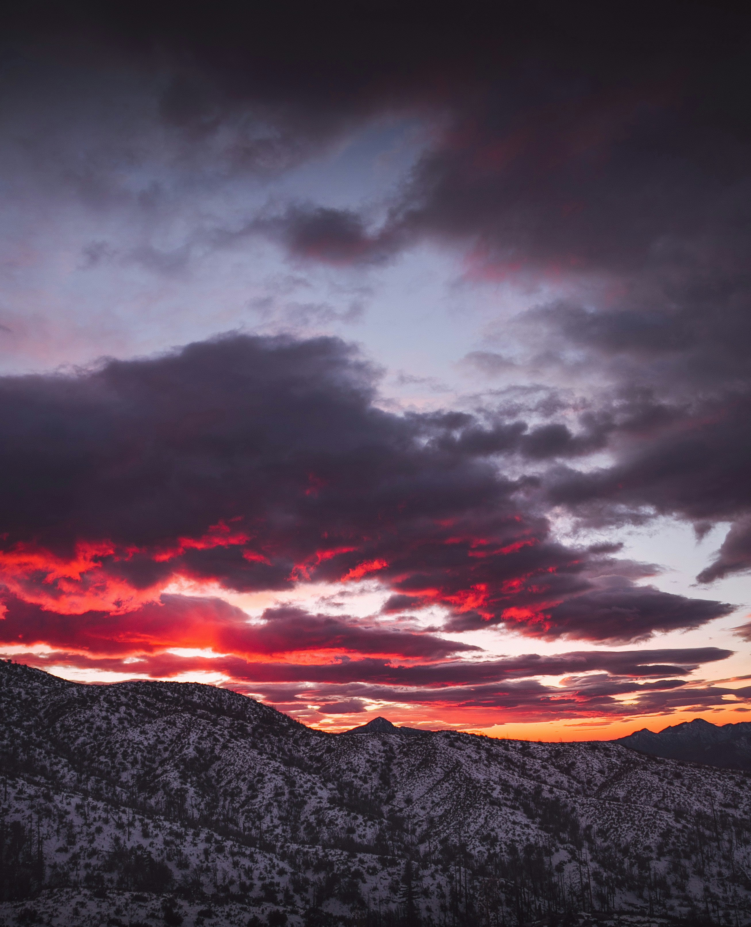 Crimson Crest at Dusk: Snow-kissed Ridge Beneath Fiery Skies