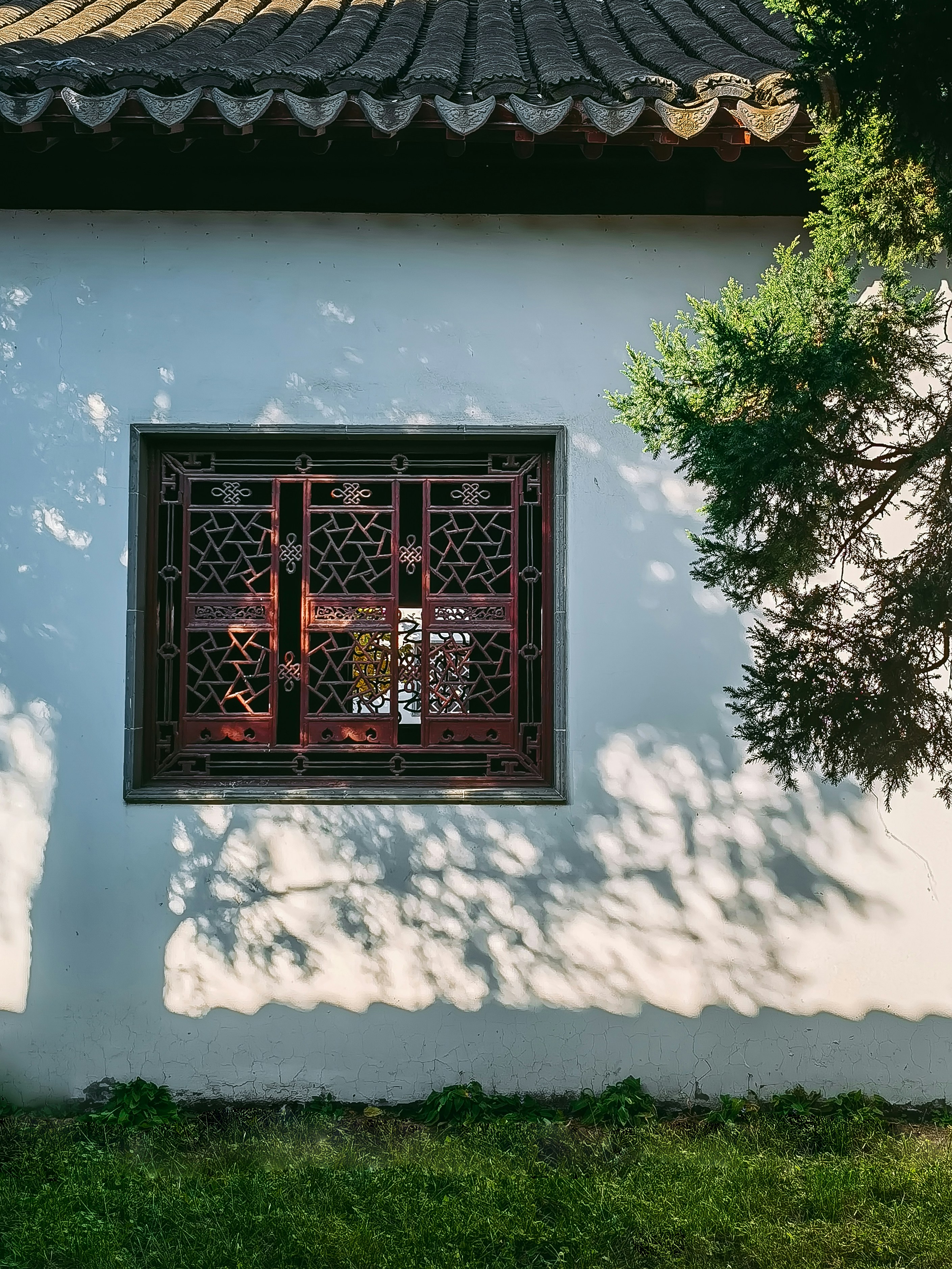 Traditional Window in Sunlit White Wall Framed by Shadow Dance