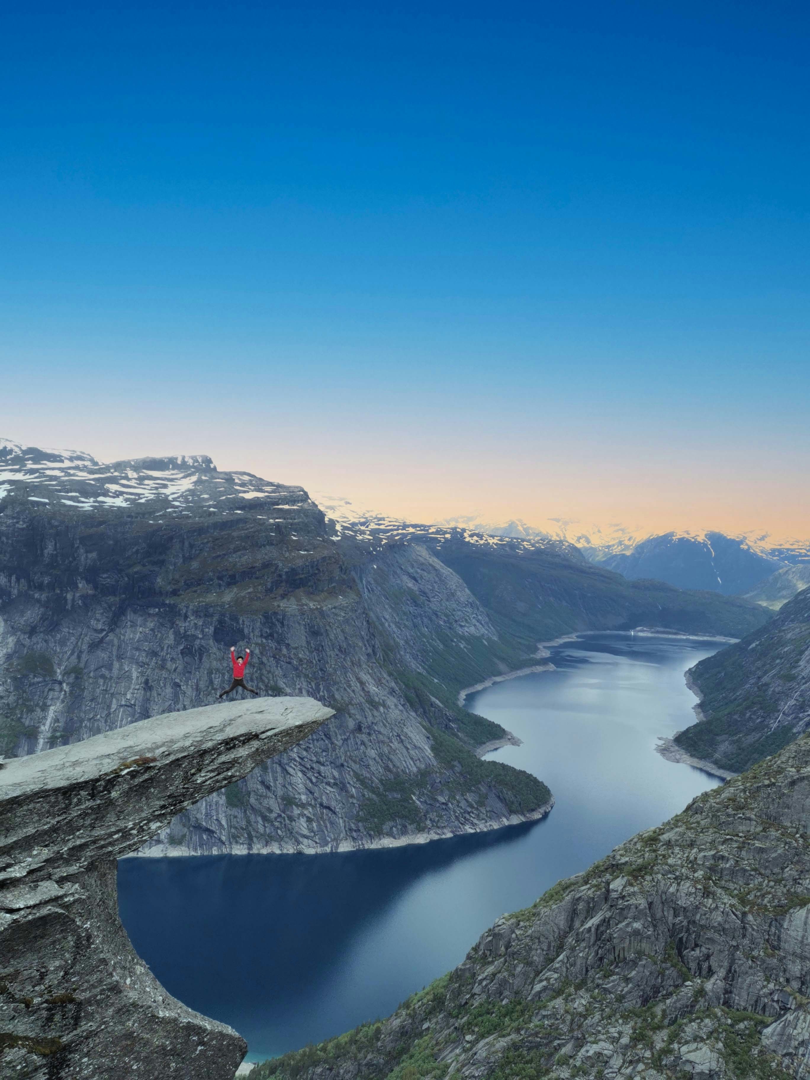 A person standing on a rock ledge above a body of water photo – Free ...
