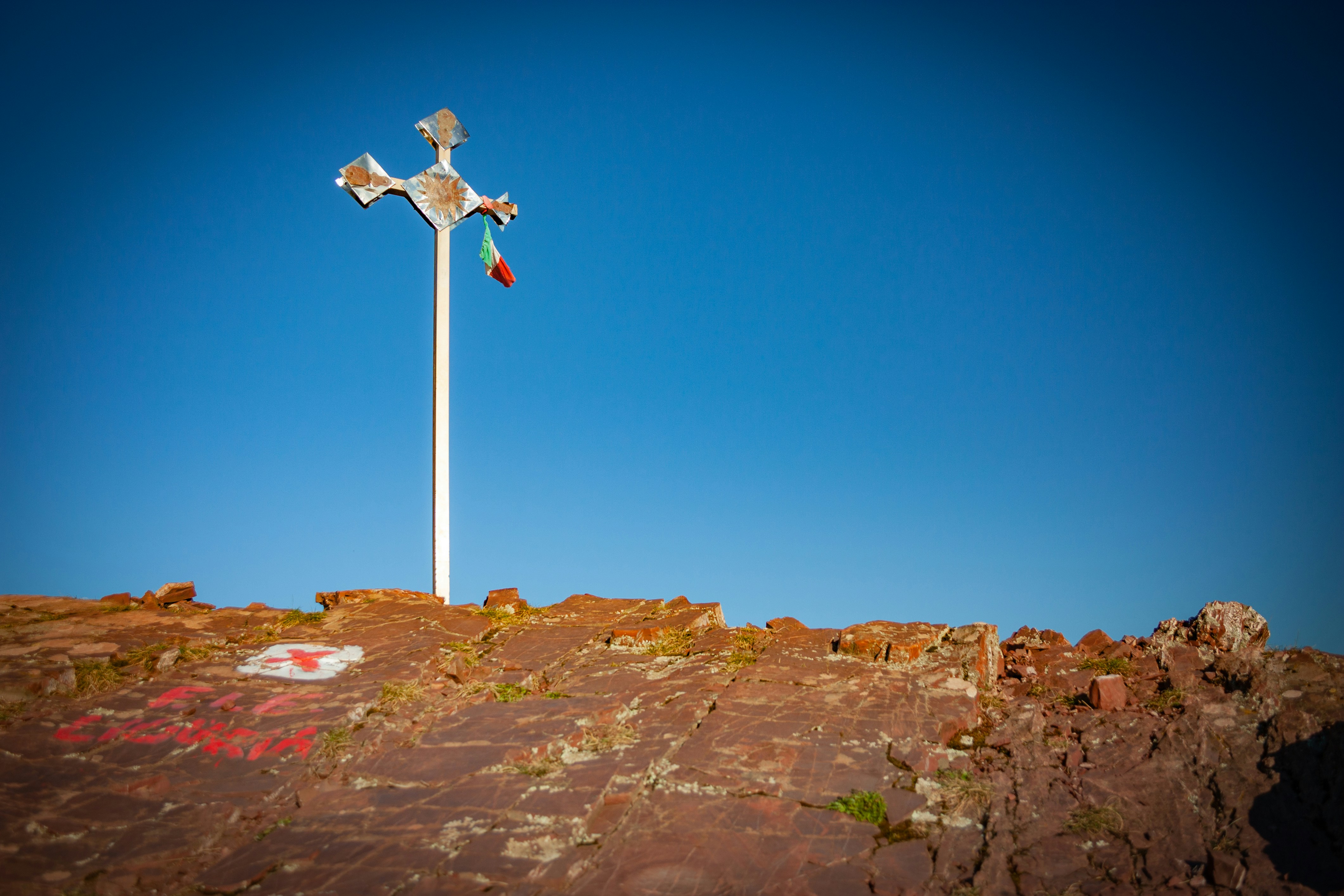 Signal on the Cliff: A Weathered Cross Against a Clear Sky