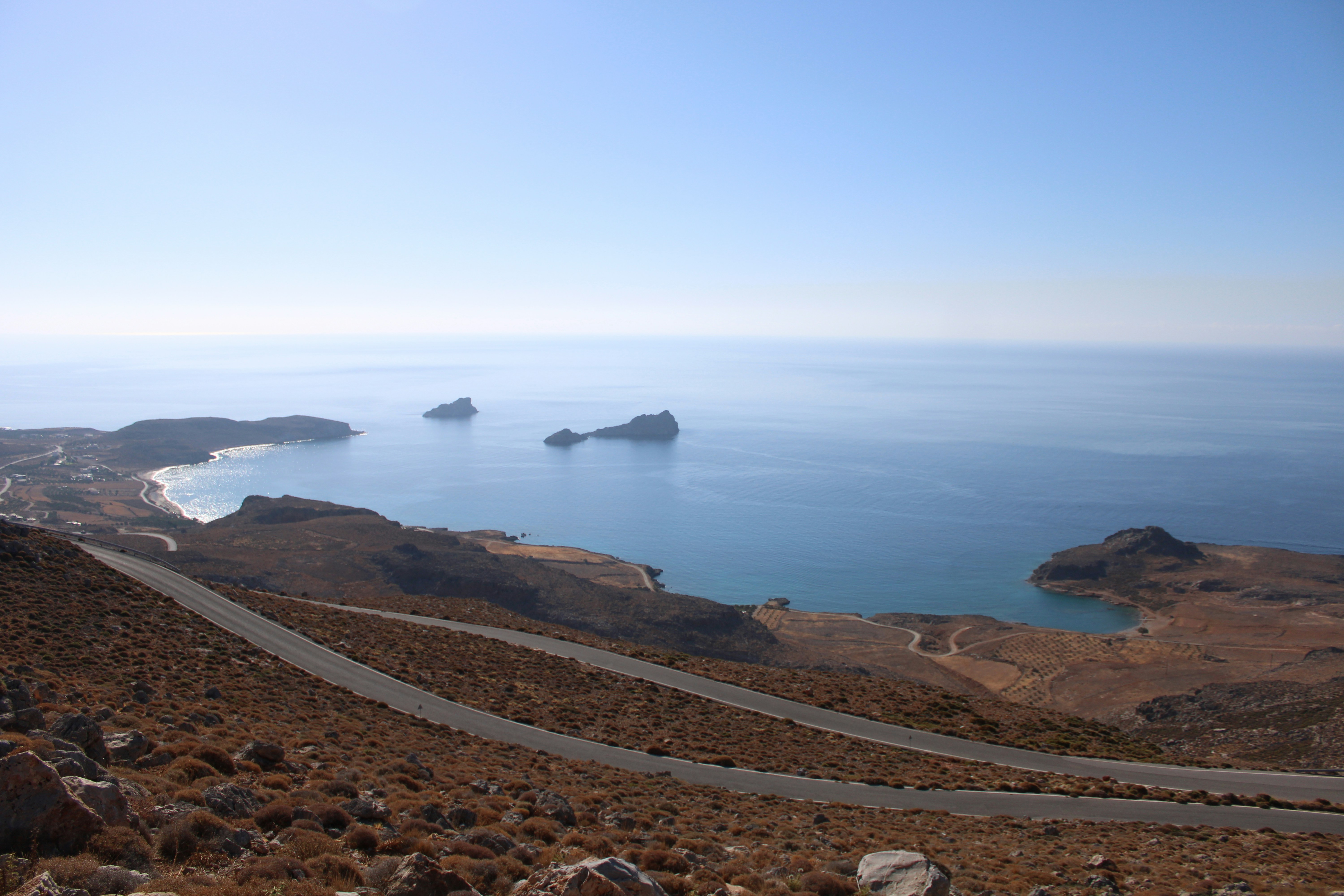 Winding Road to the Quiet Sea: Red Hills Meet a Cerulean Horizon