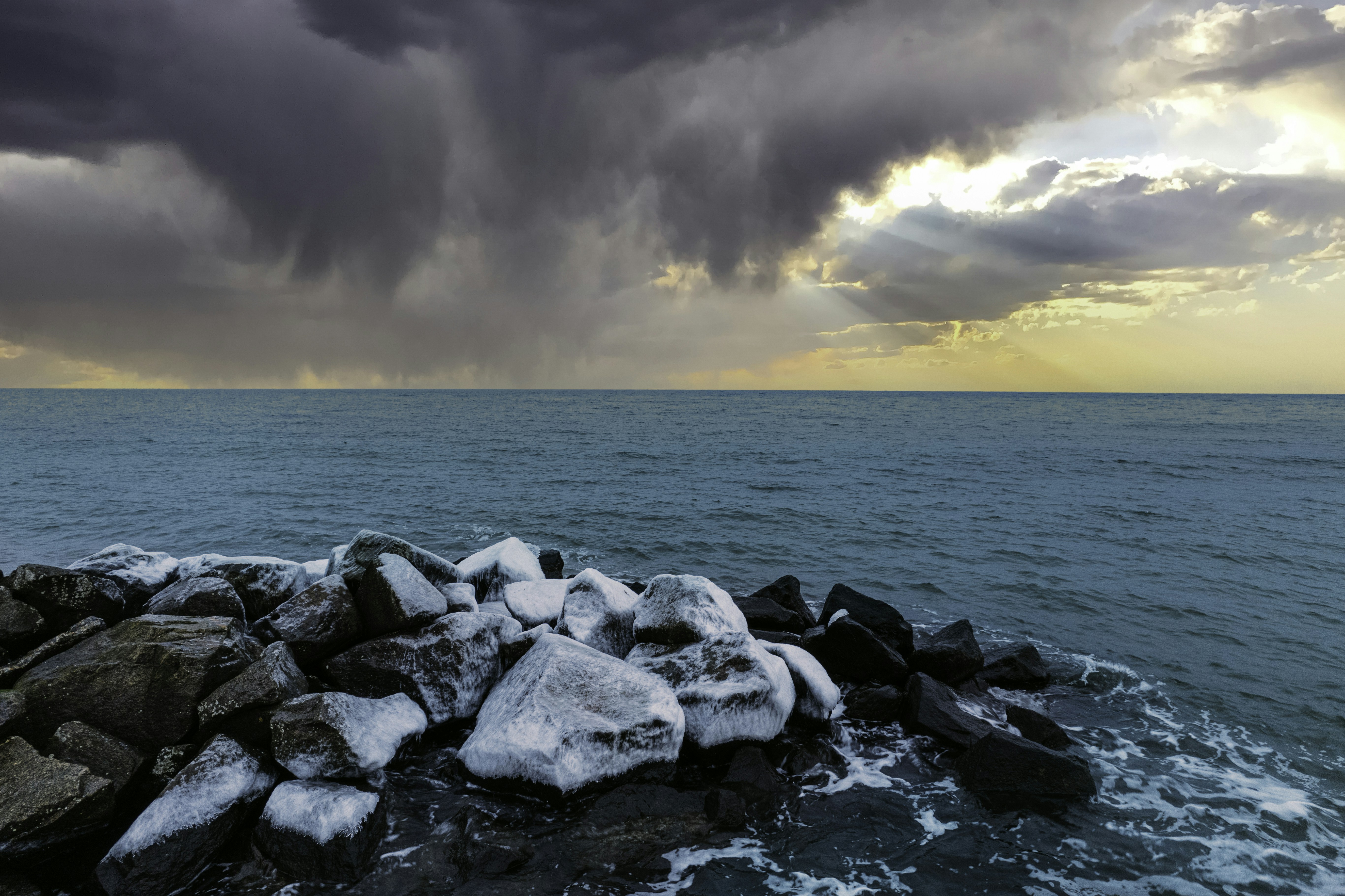 Snow-Flecked Breakwater Beneath a Storm-Burnished Horizon