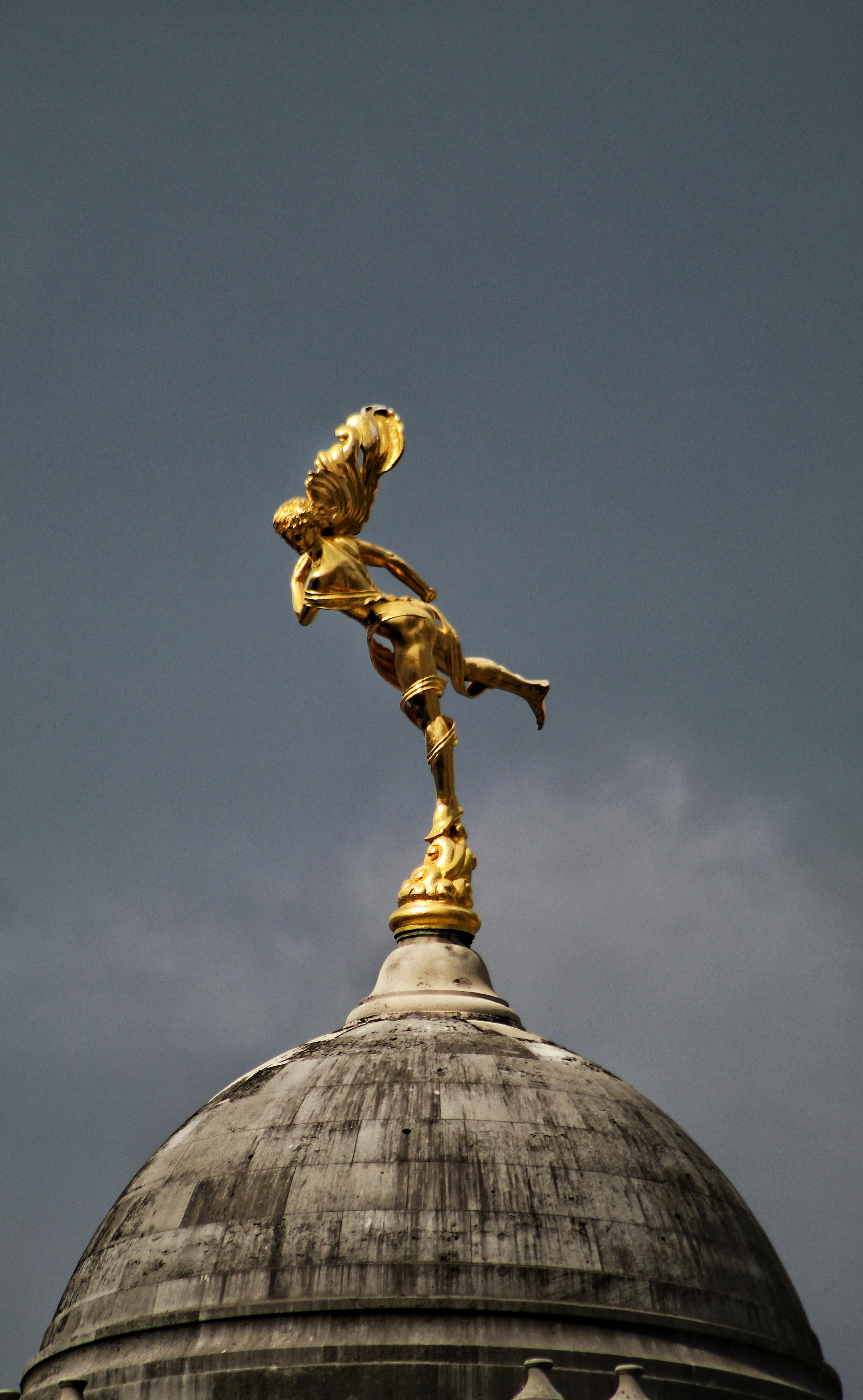 Gilded Sentinel atop a Weathered Dome Against a Quiet Sky